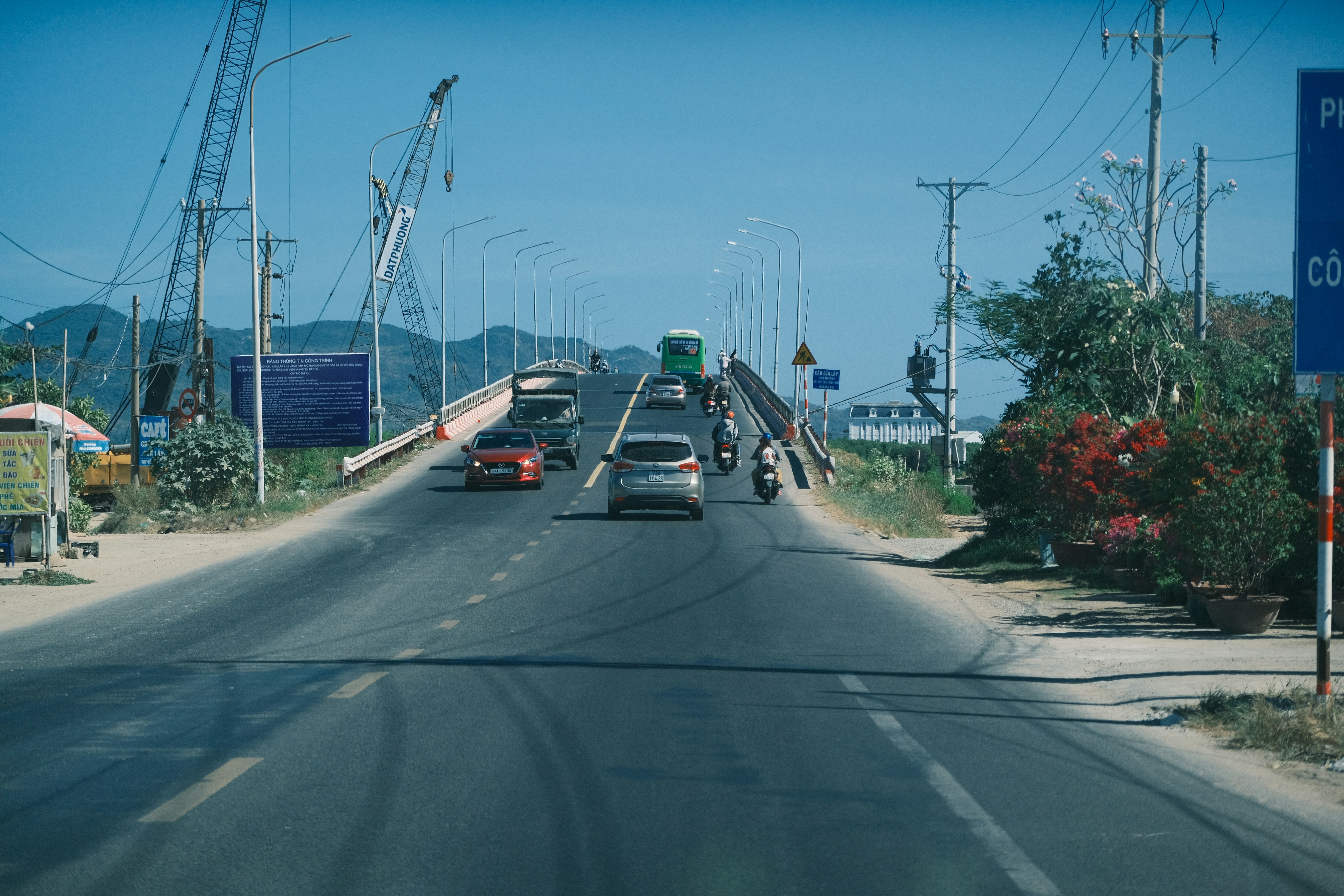 Horizon Climb: Traffic on a Sunlit Coastal Bridge Under a Clear Blue Sky