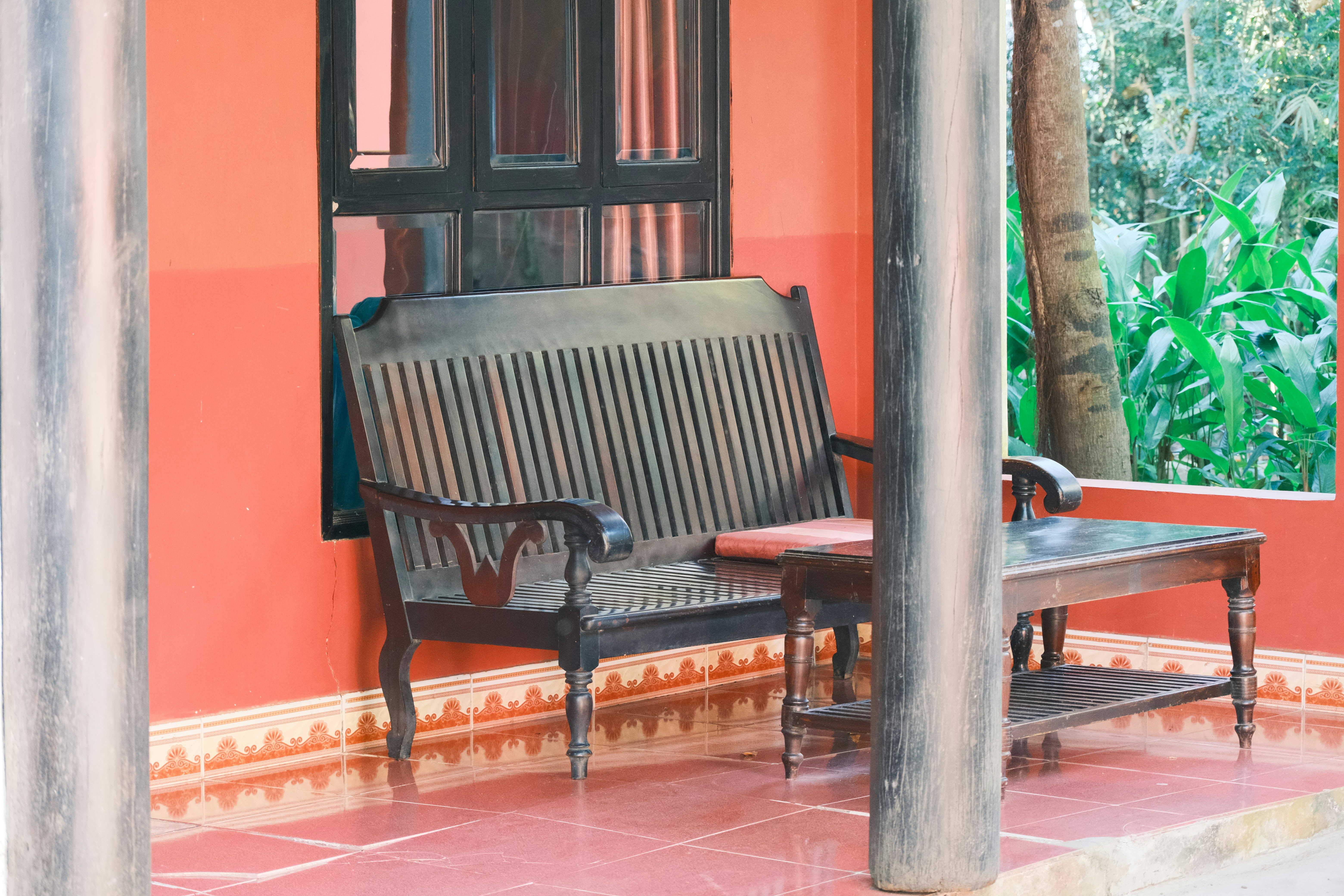 Coral-Walled Veranda Bench: Quiet Seating Framed by Columns and Tropical Greenery