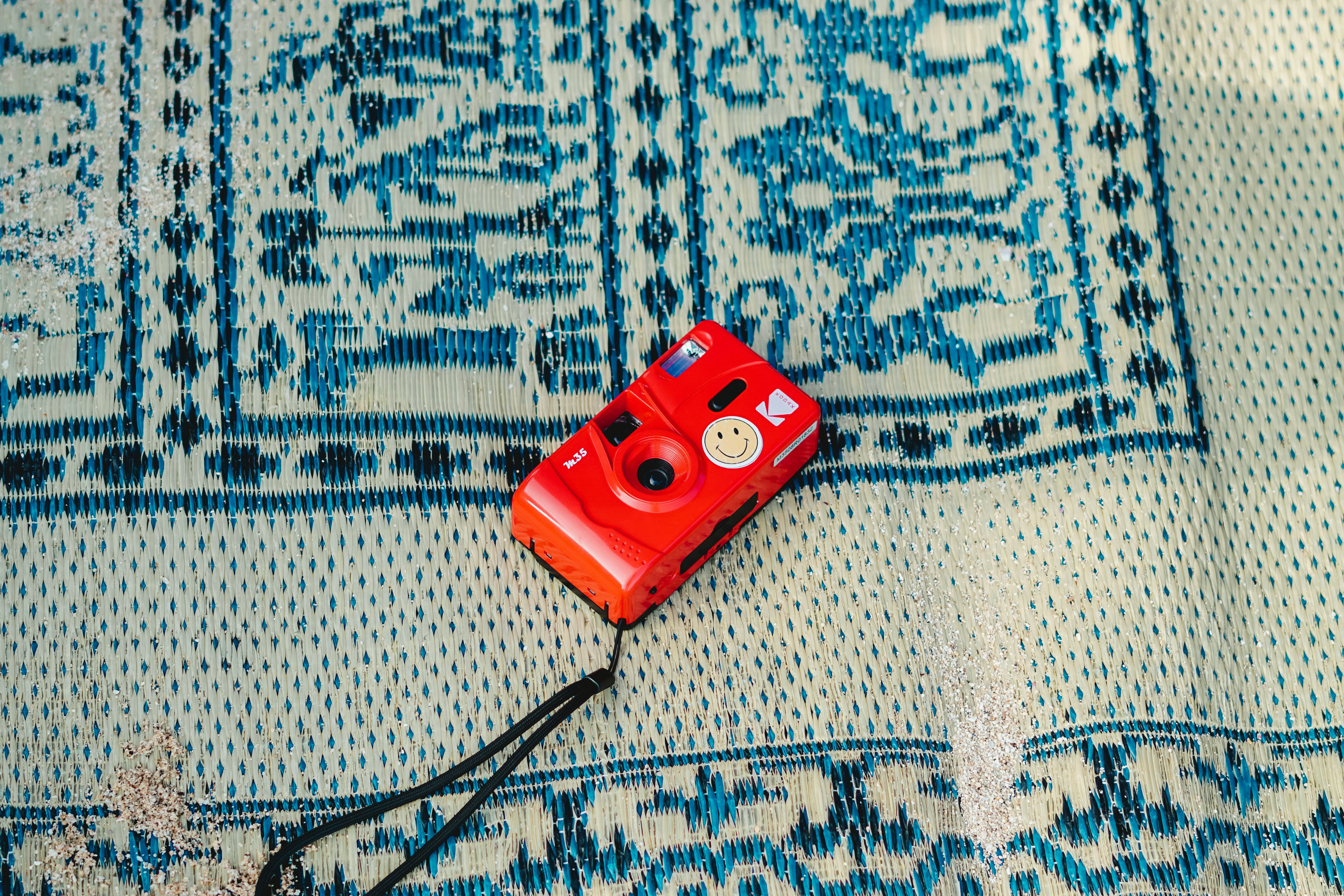 Un appareil photo rouge posé sur un tapis bleu photo – Image gratuite ...