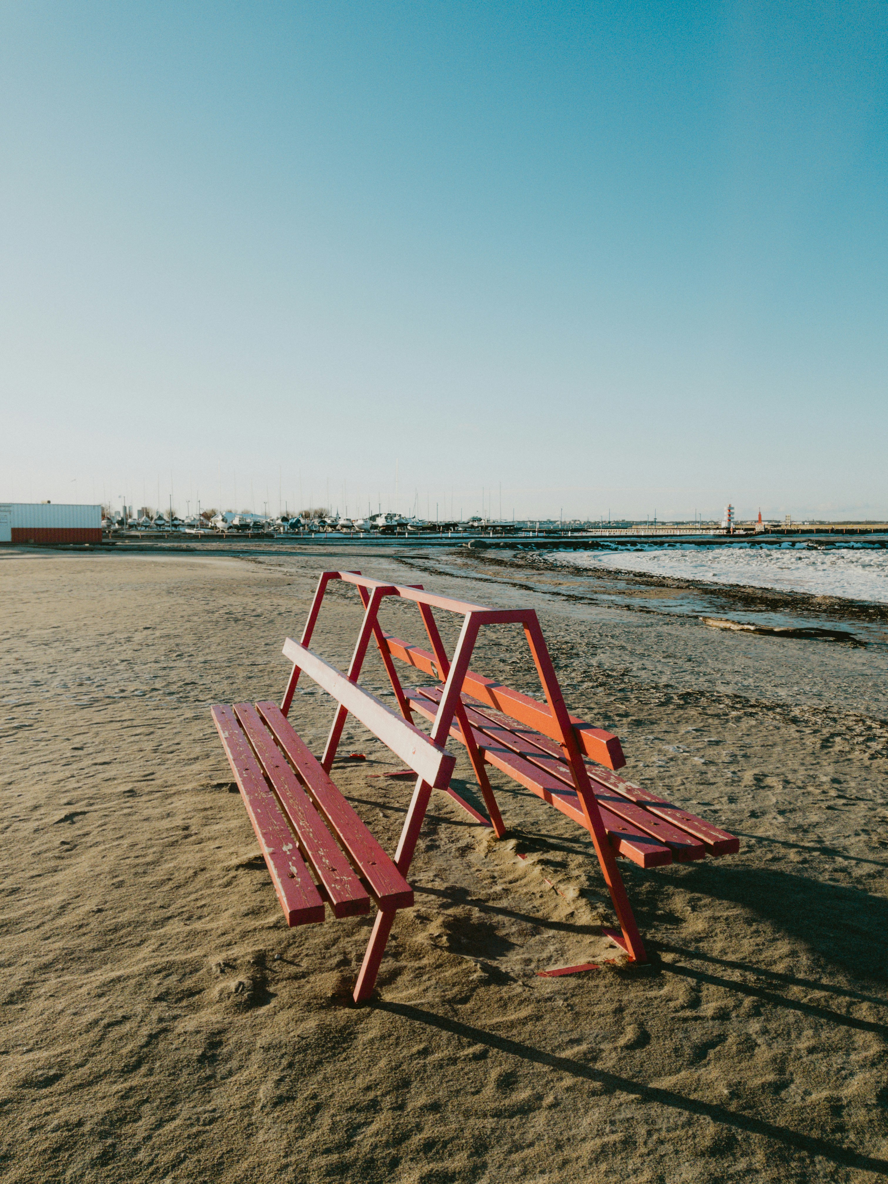 Crimson Bench by the Quiet Seaside Marina Under a Clear Blue Sky