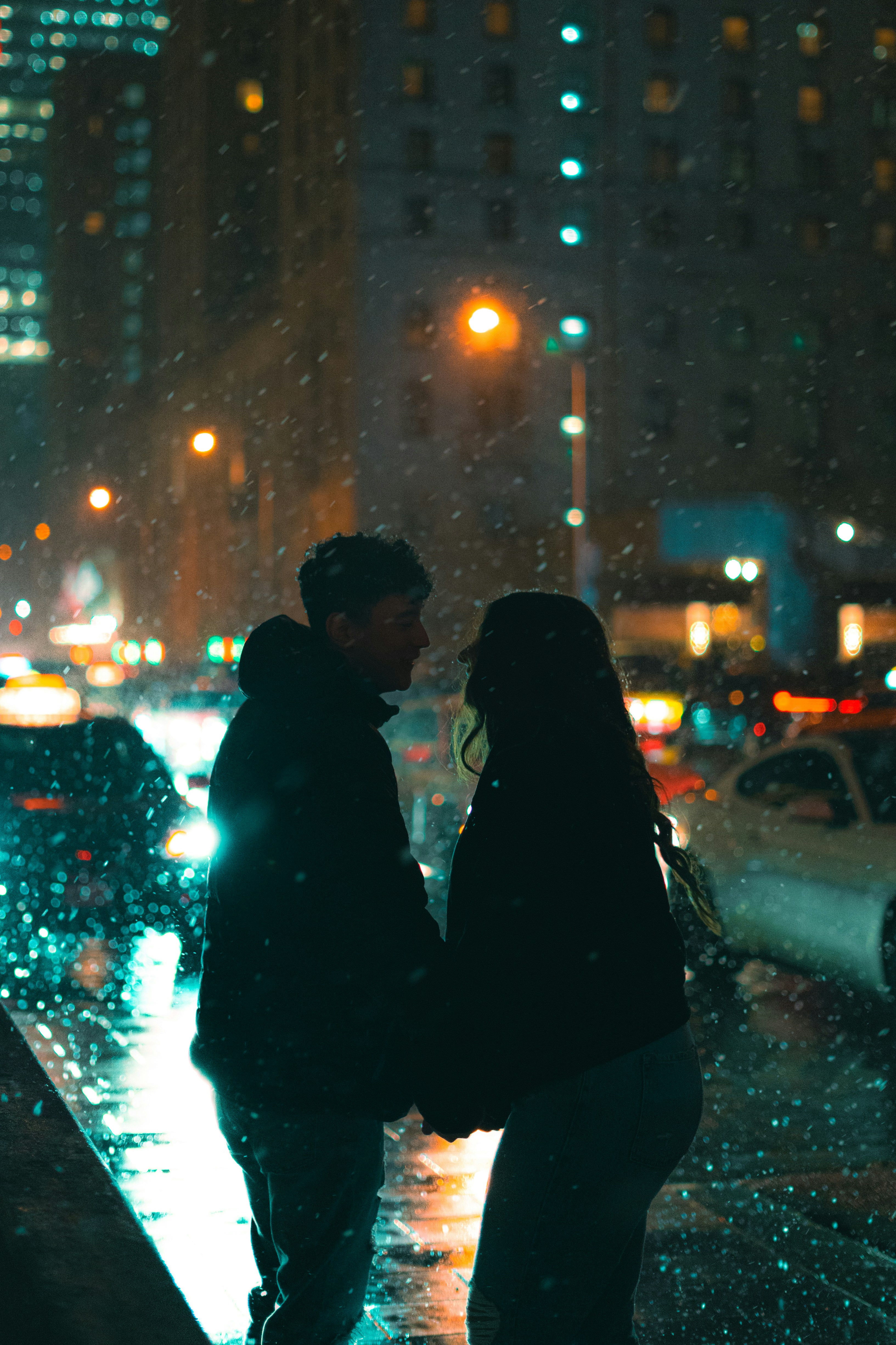 Silhouettes in Snow: Nighttime Embrace Under Neon City Lights