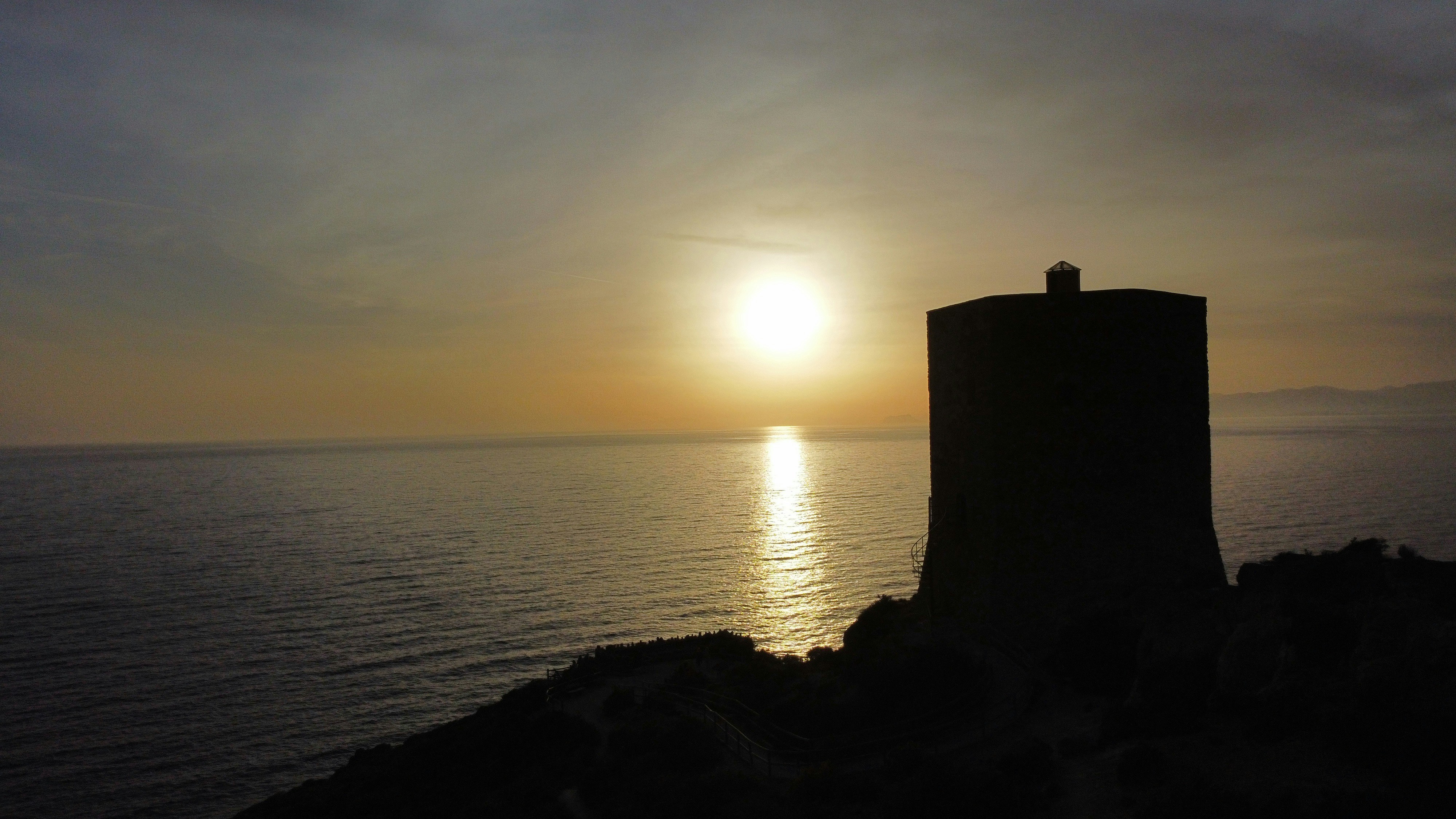 Sunlit Silhouette: A Lone Turret Above The Quiet Sea