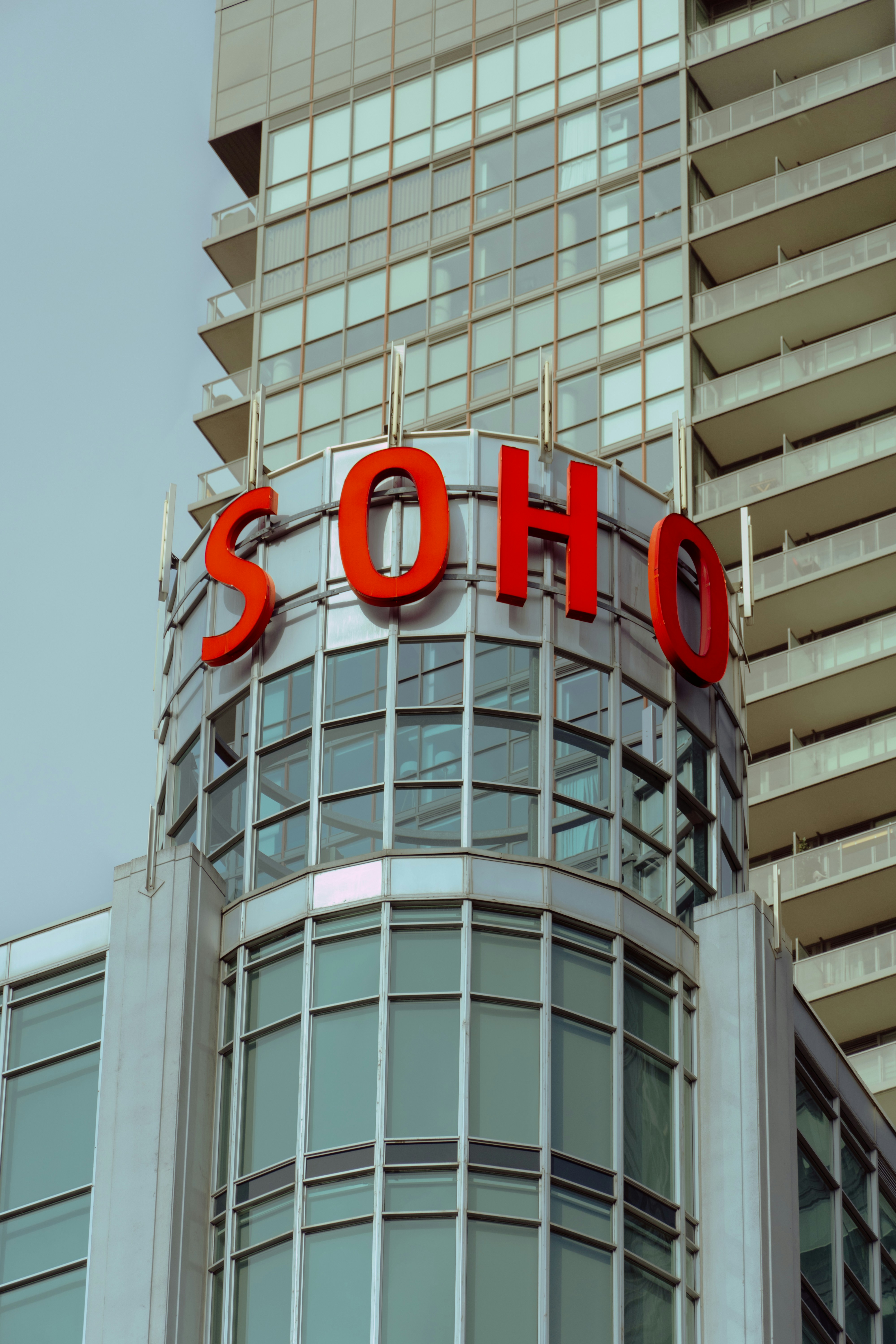 SOHO Sculpted in Glass: Red Letters on a Curved Facade Against a Modern Skyline