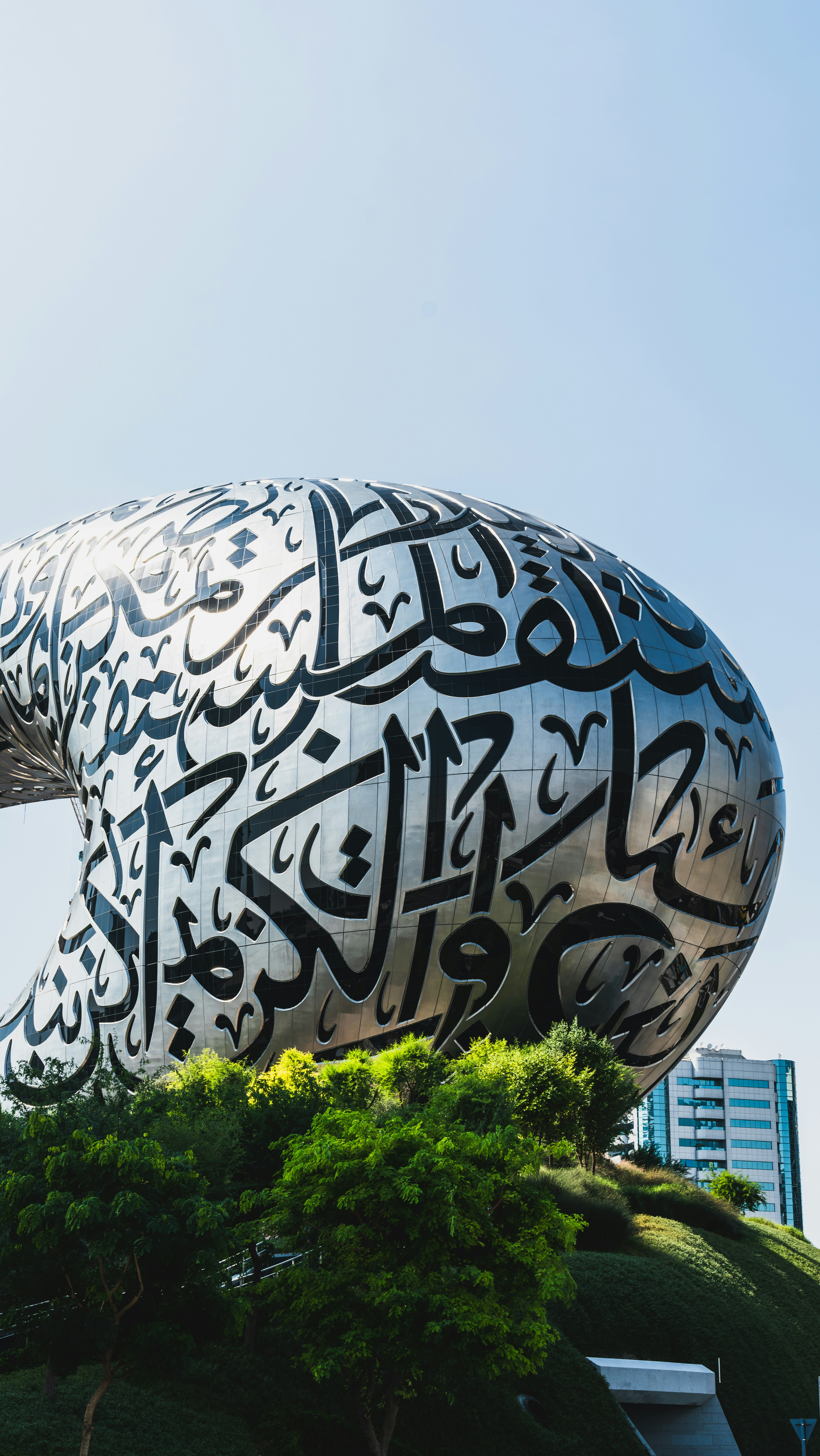 Scripted Sphere: A Shiny Arabic Calligraphy Balloon Nestled Above Greenery