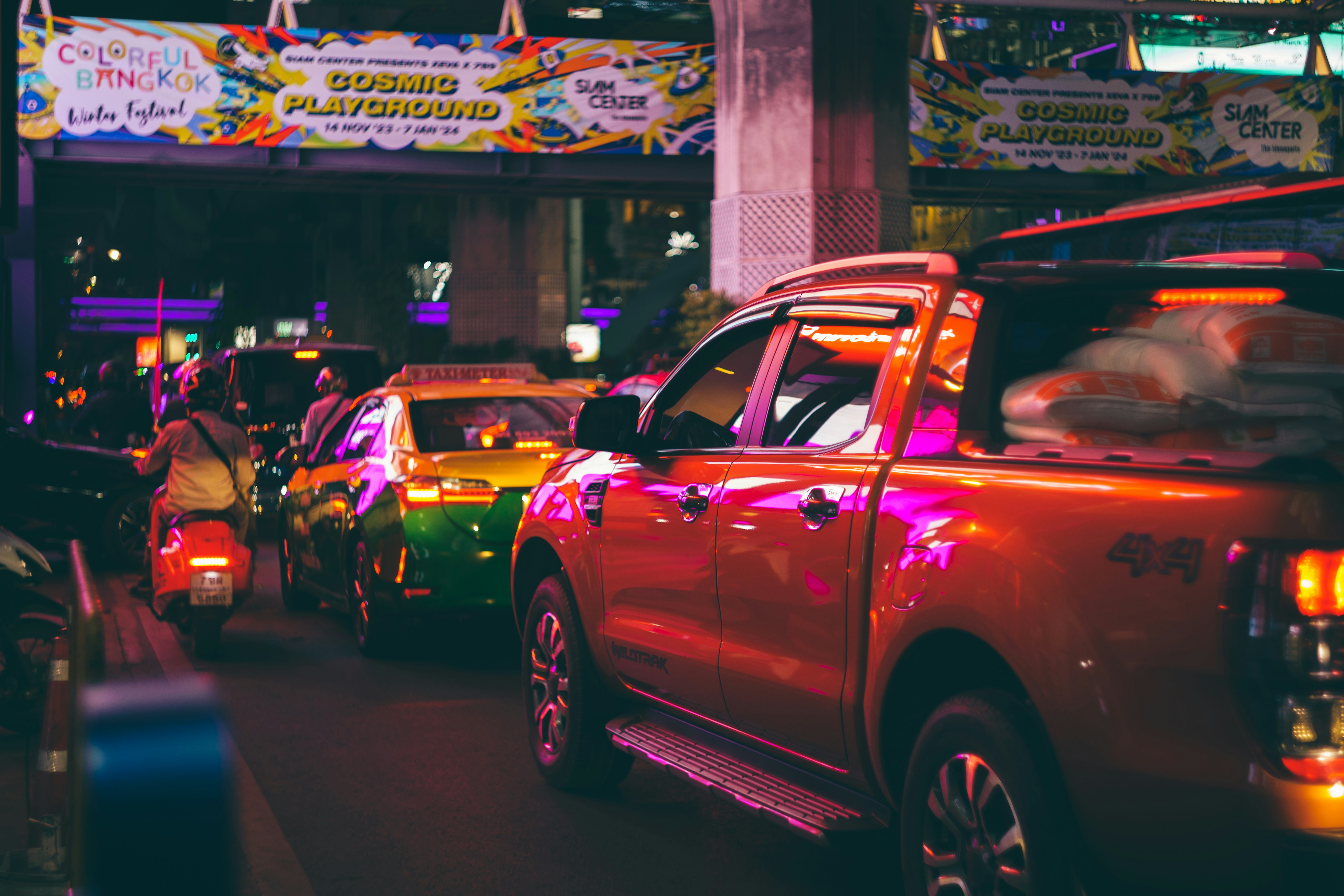 Crimson Pickup Under Neon Arches: A Night Drive Through Colorful City Lights