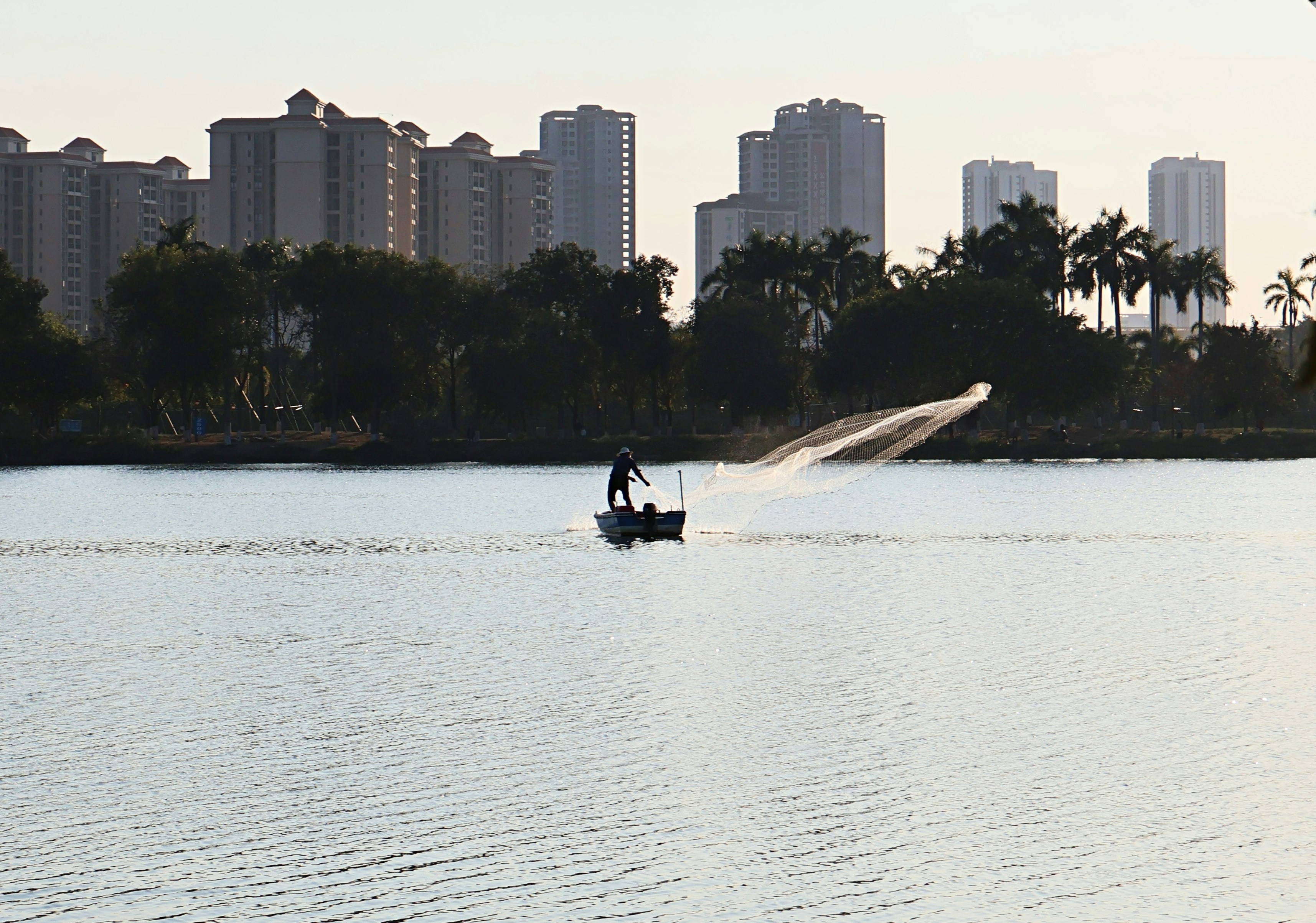 Lone Boat, City Backdrop: Spray Arc Over a Quiet Urban Lake