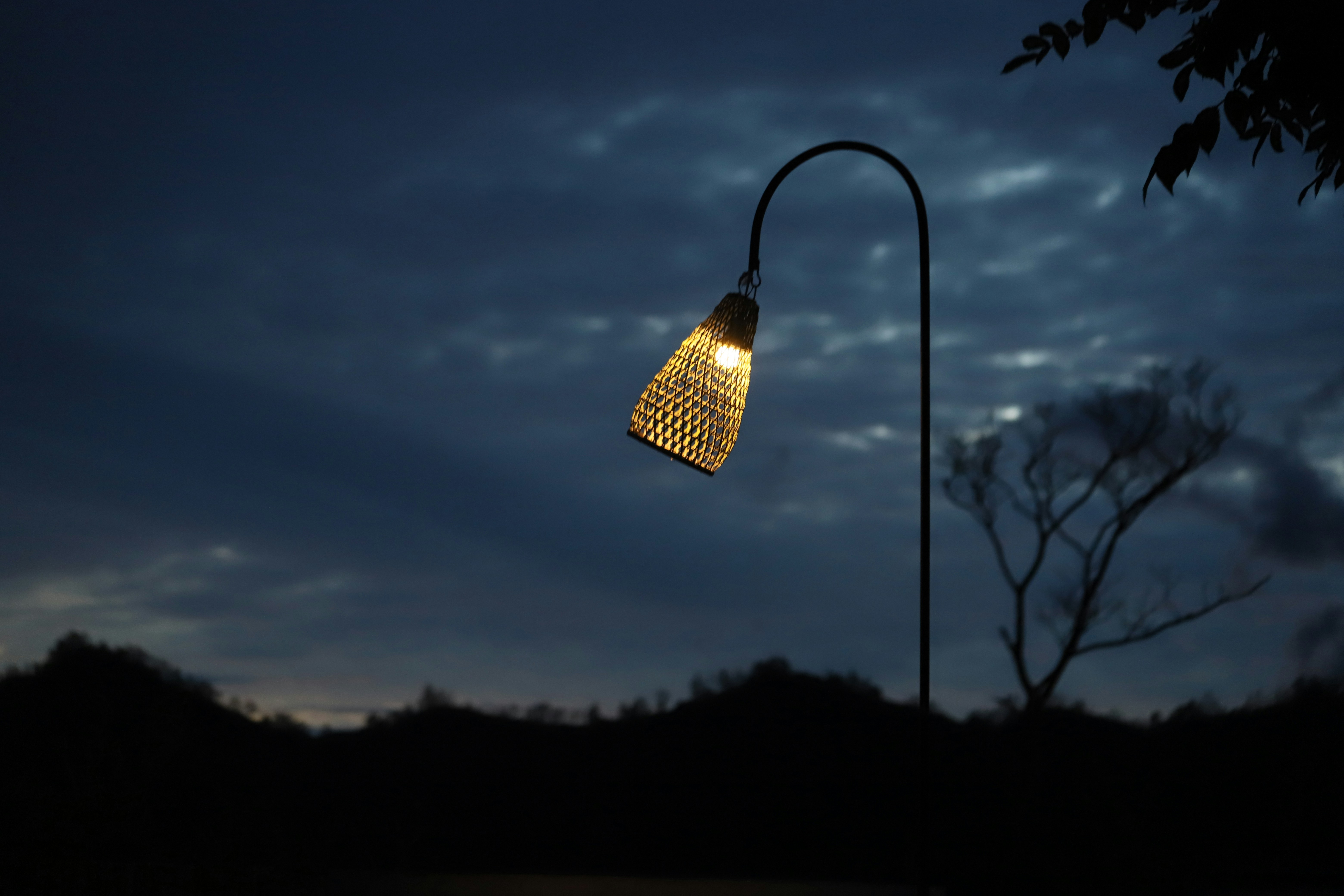 Amber Thread of Evening Light: A Lone Lamp Against the Dusk Sky