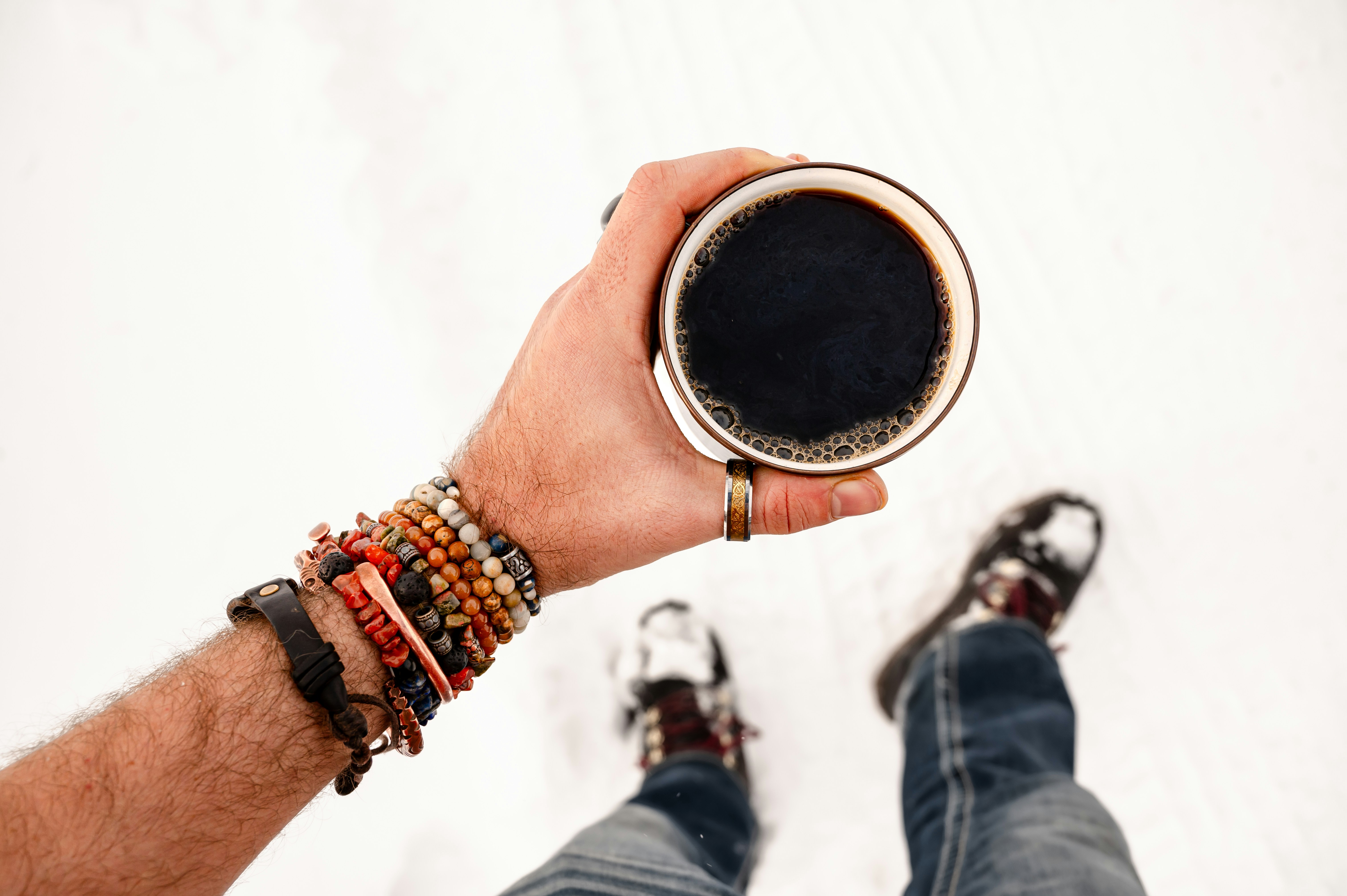 Top-Down Morning Brew: Coffee, Bracelets, and Snow Underfoot