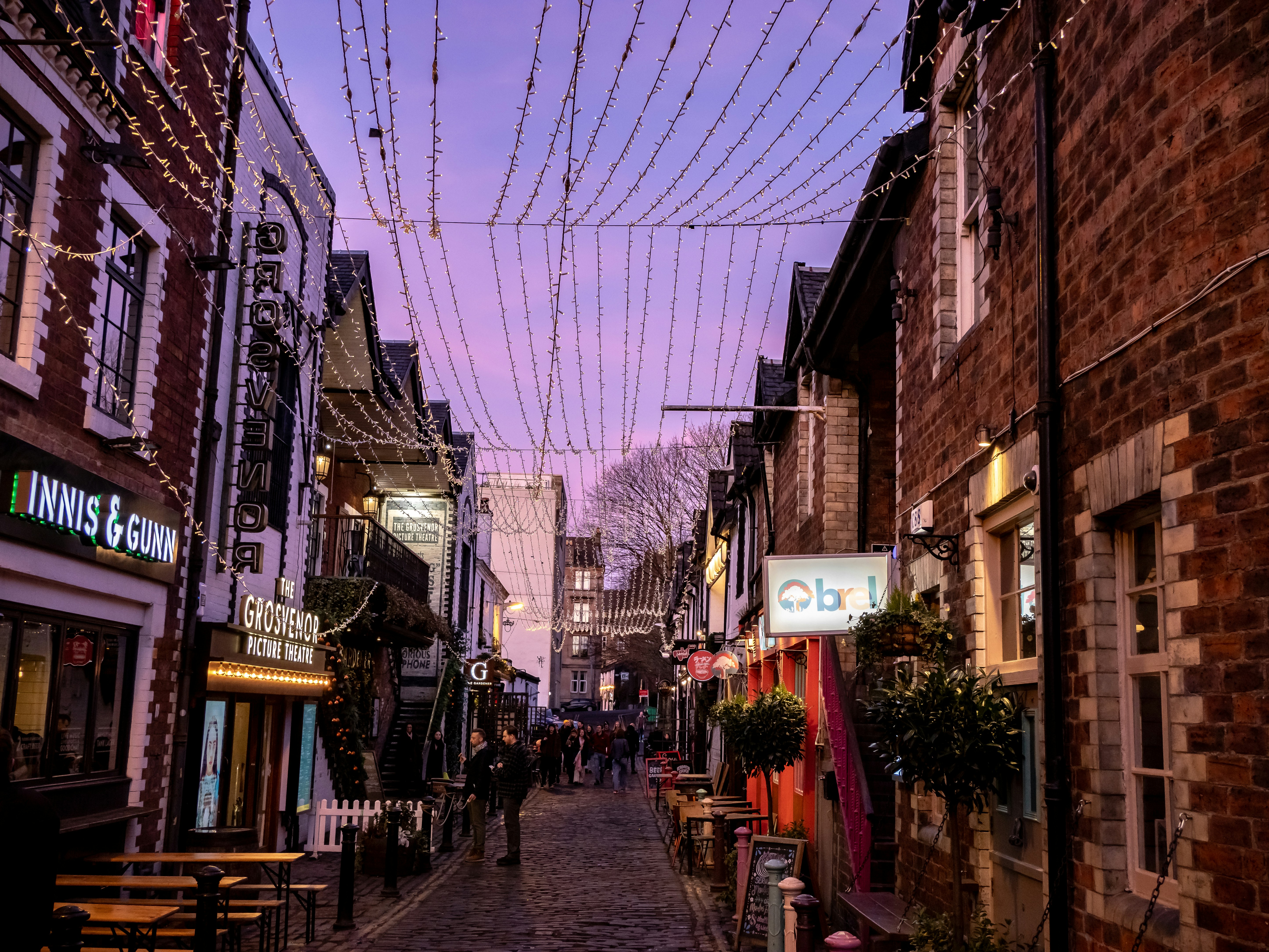 A city street lined with brick buildings and string lights photo – Free ...