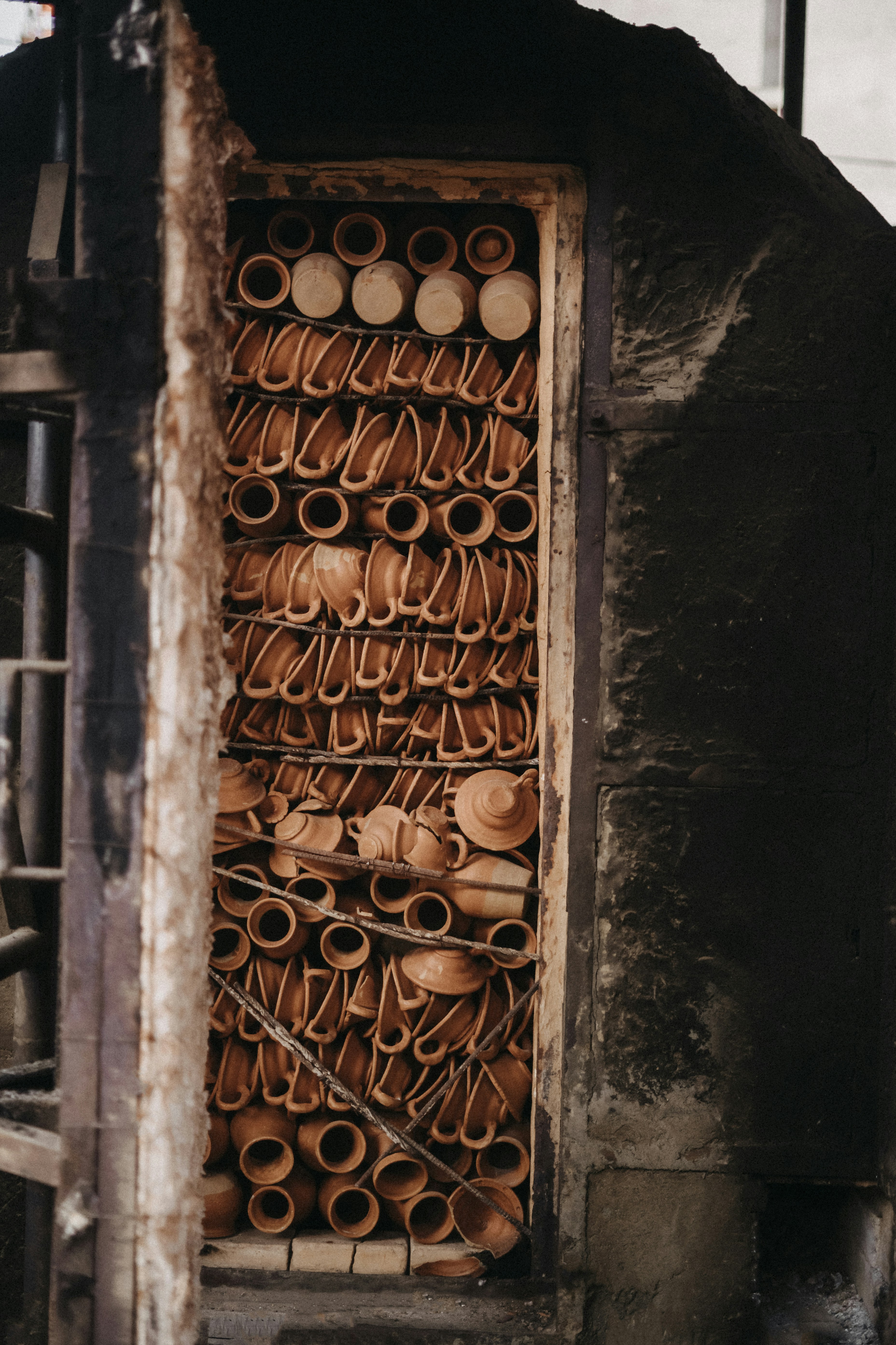 Stacks of terracotta tubes and bowls in a rustic kiln