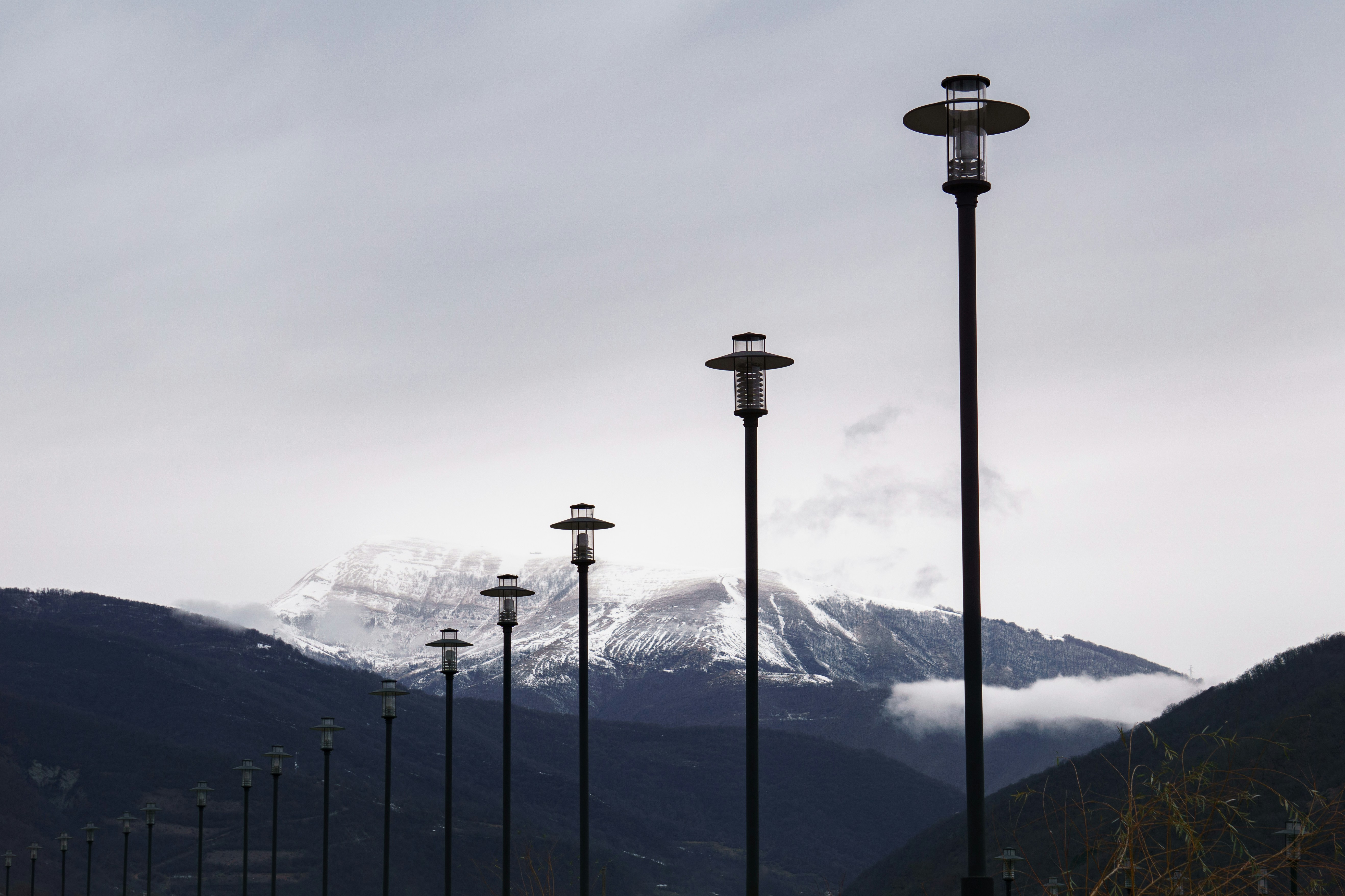 A Spine of Light: Lantern Poles Marching Beneath Alpine Clouds