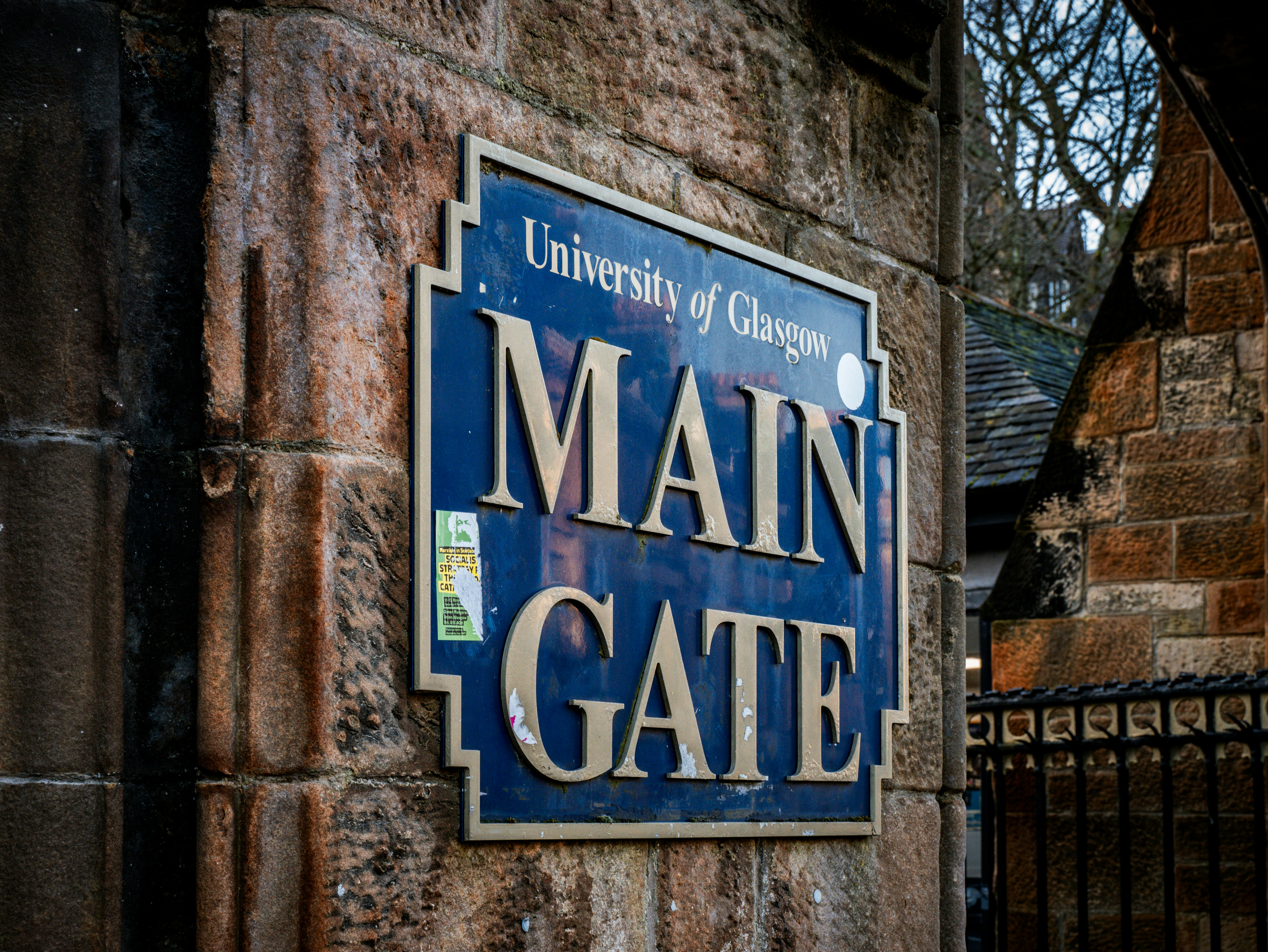 A blue sign that reads main gate on a brick wall photo – Free ...