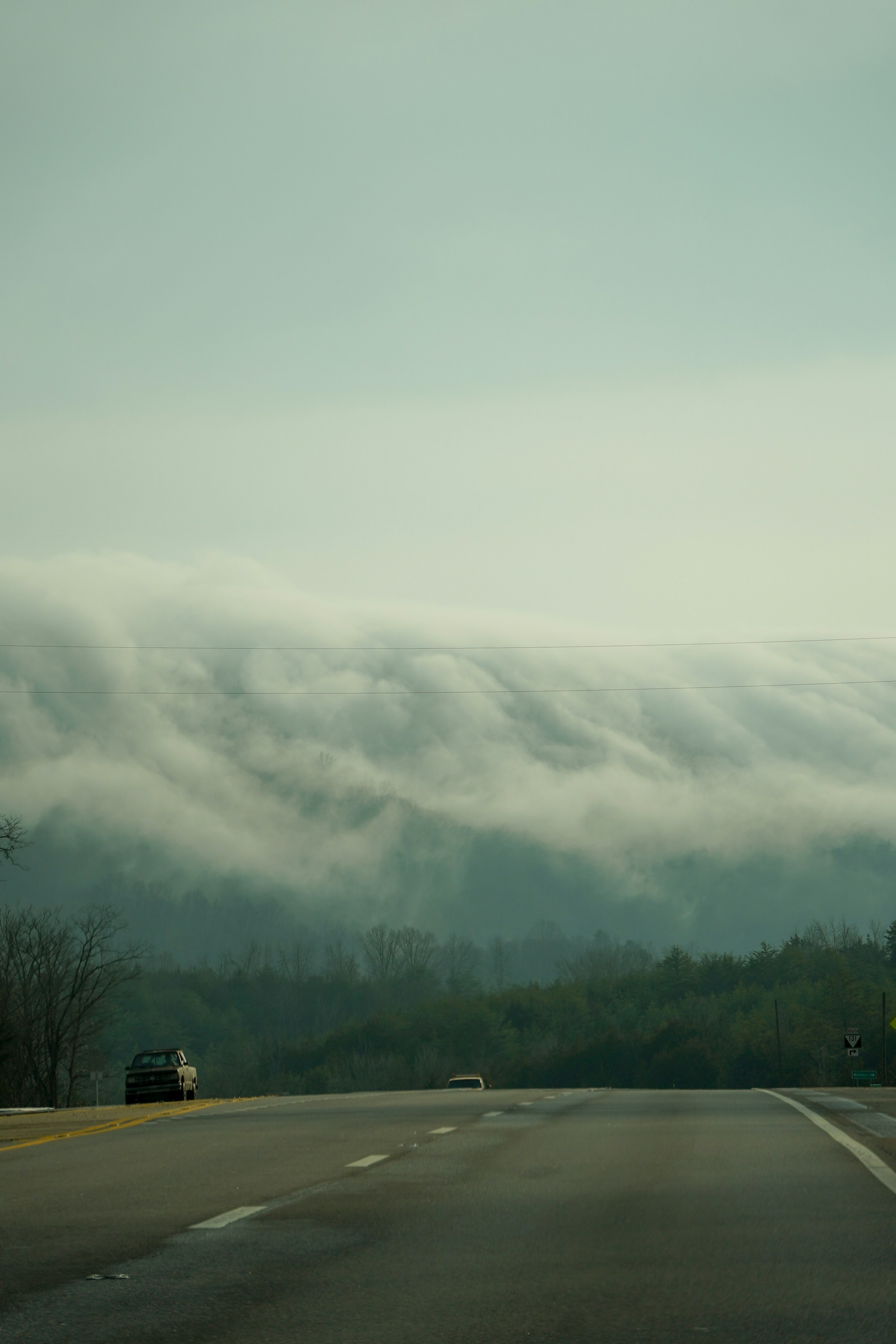 Horizon in the Mist: A Quiet Highway Carves Through Layered Clouds