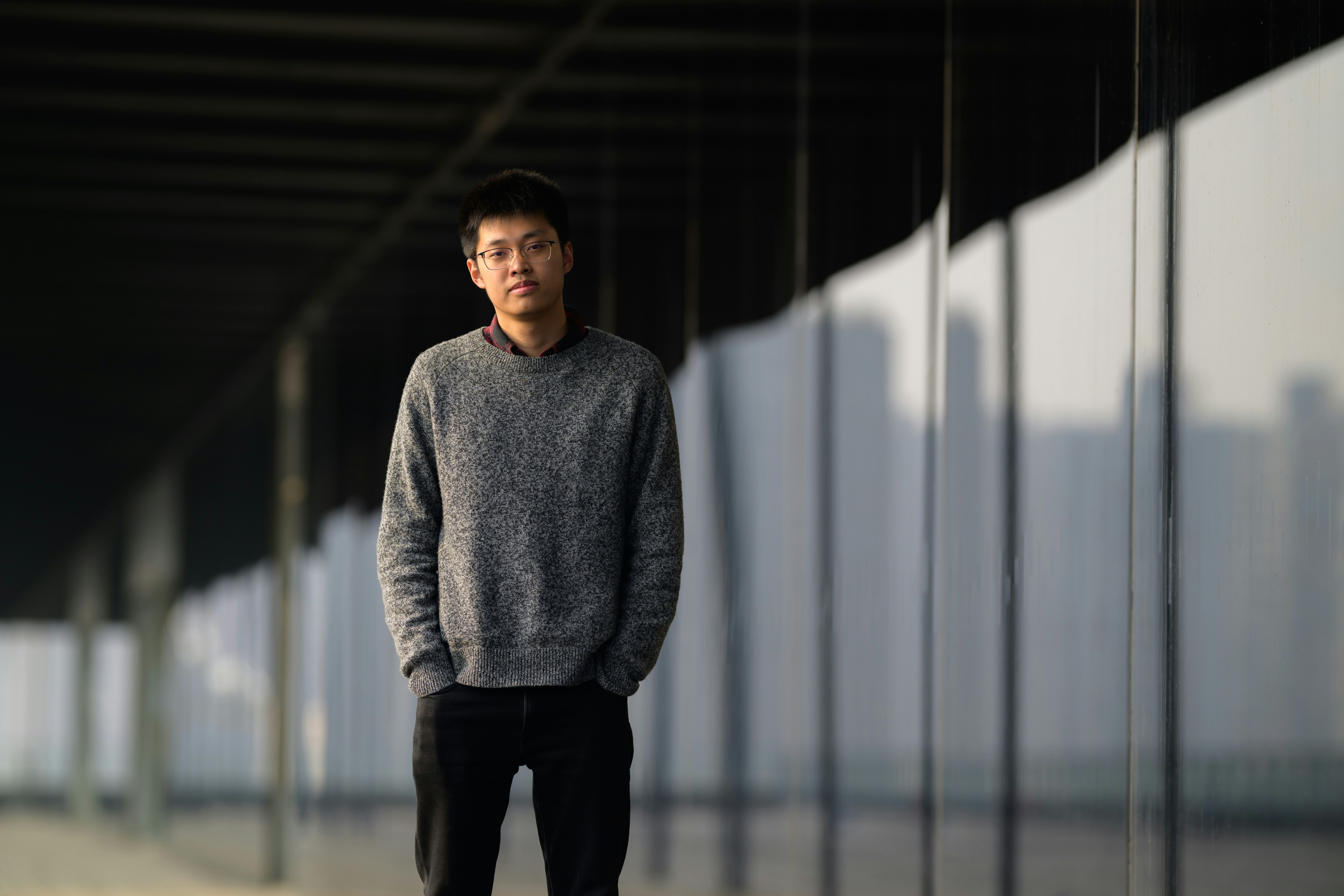 A man standing in a long hallway with metal bars on the sides of it