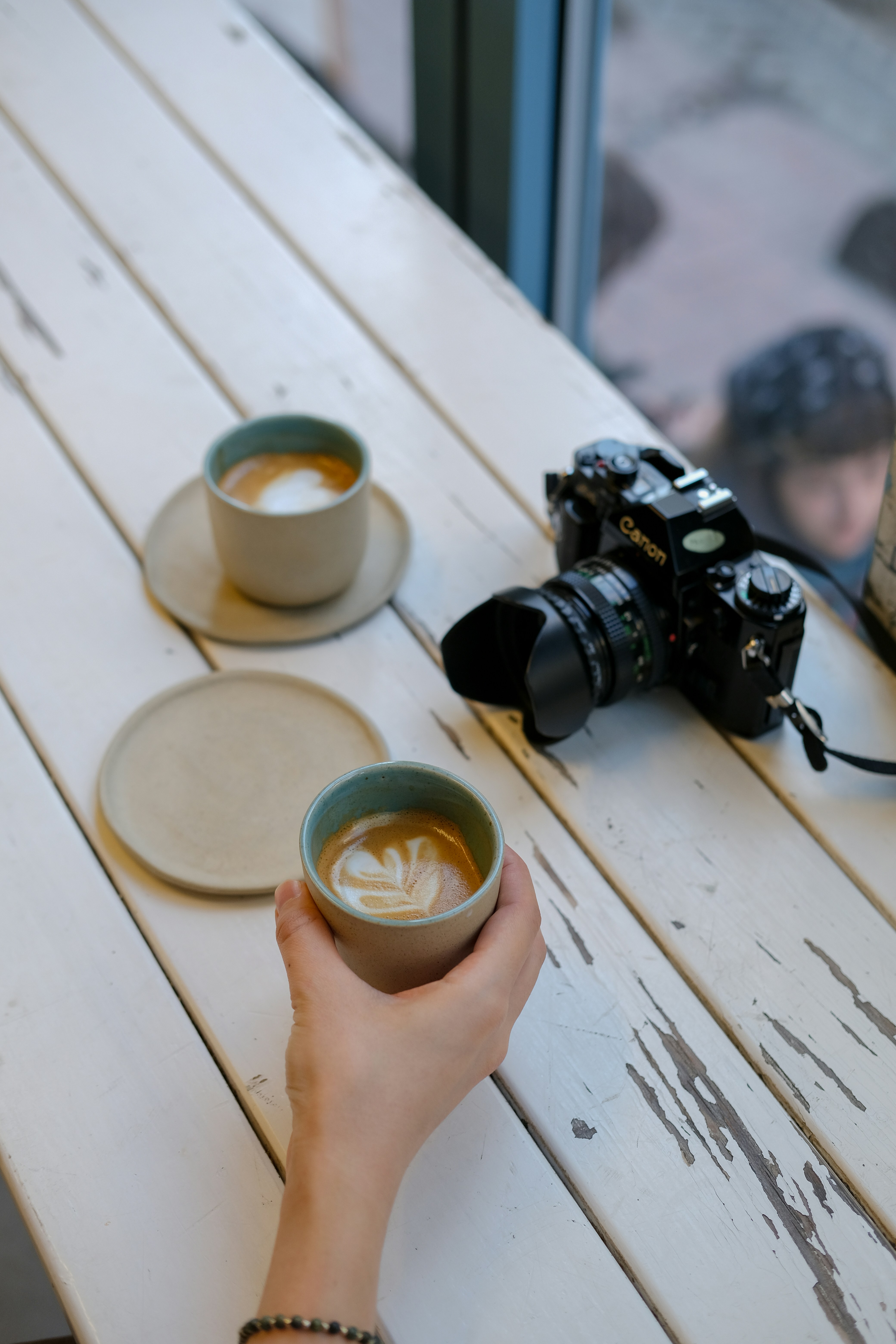 A person holding a cup of coffee in front of a camera photo – Free ...