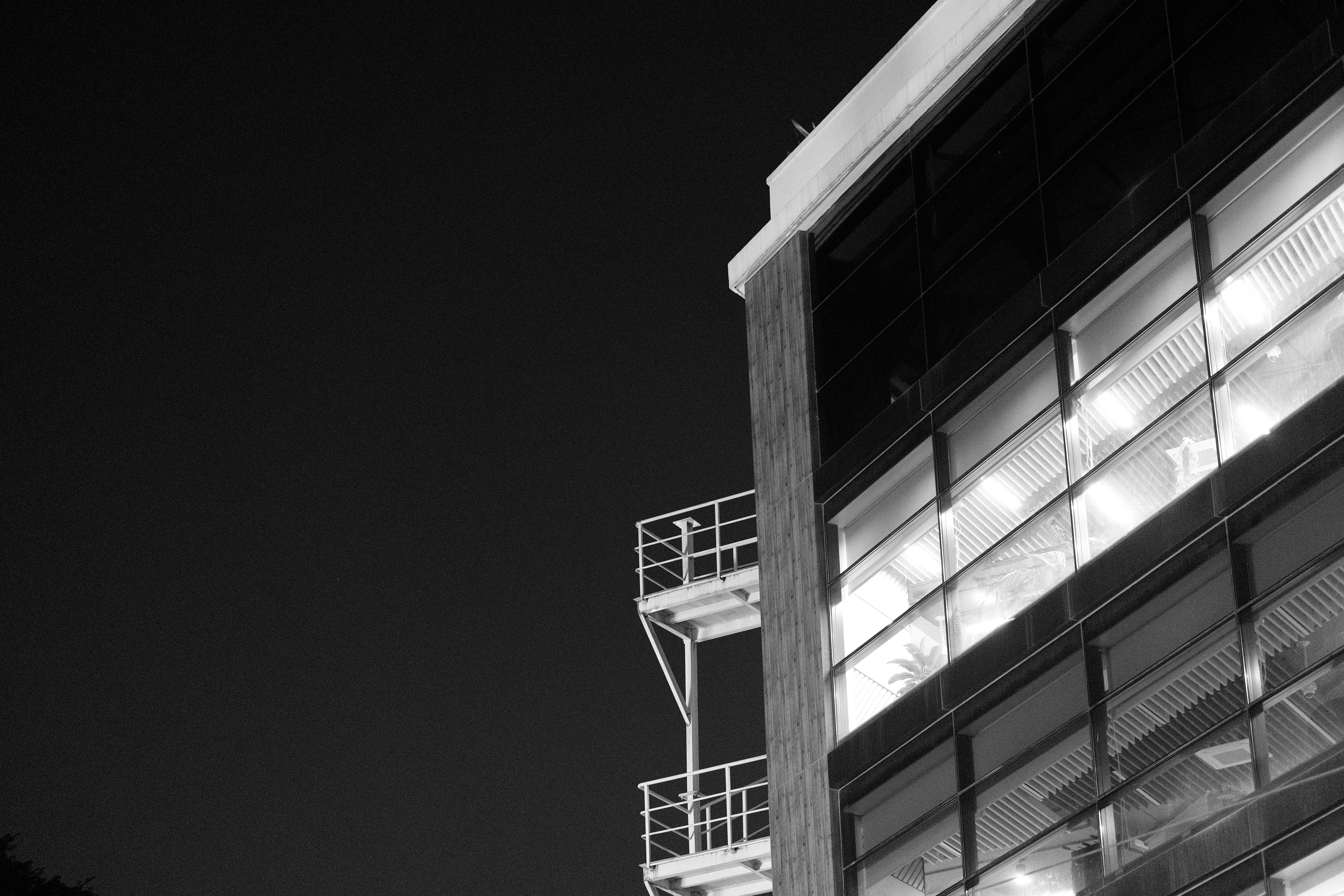Night Edge: Steel Fire Escape Clings to a Glass Tower