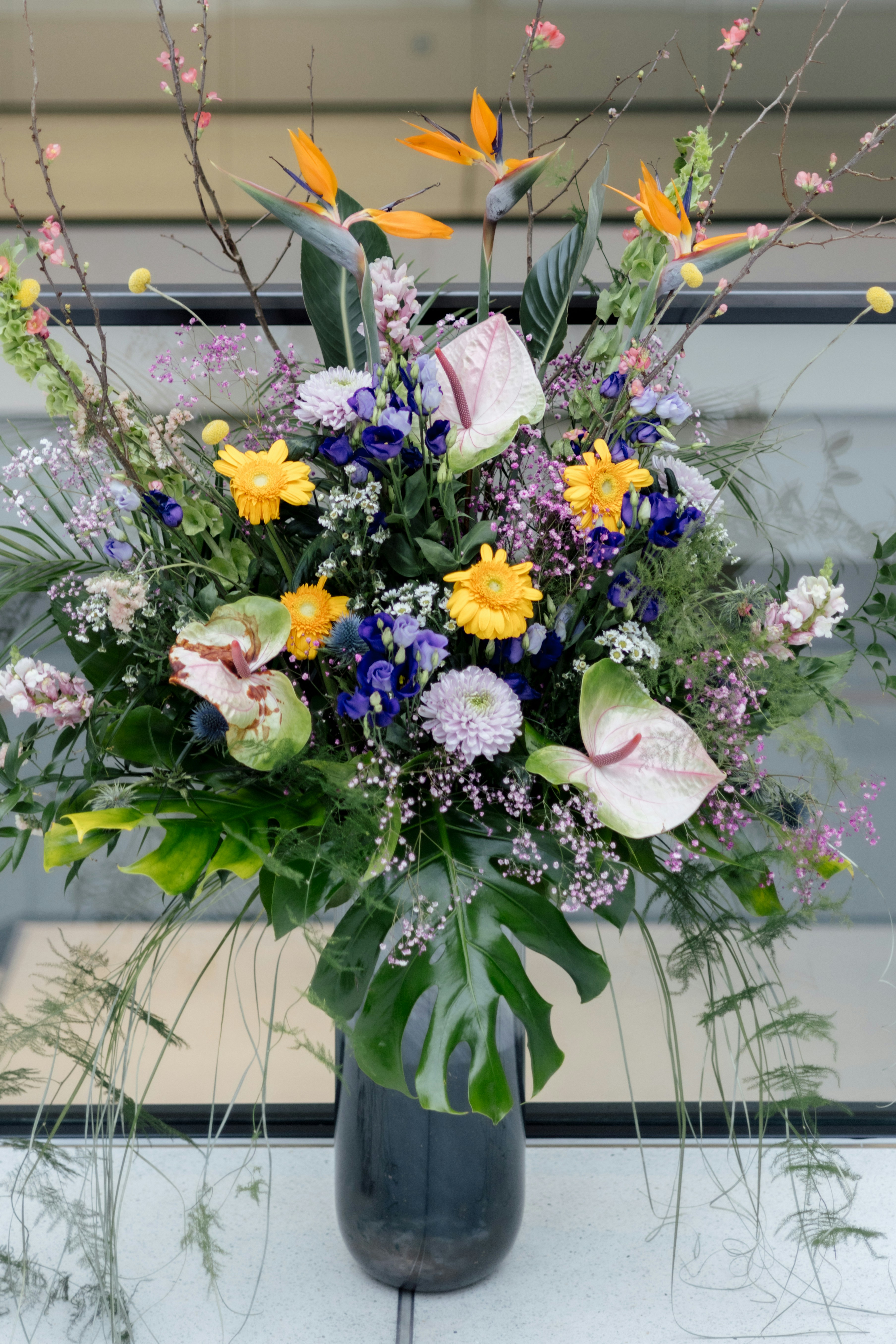 Center of Color: A Dense Bouquet of Bird of Paradise and Sunlit Blossoms in a Dark Vase