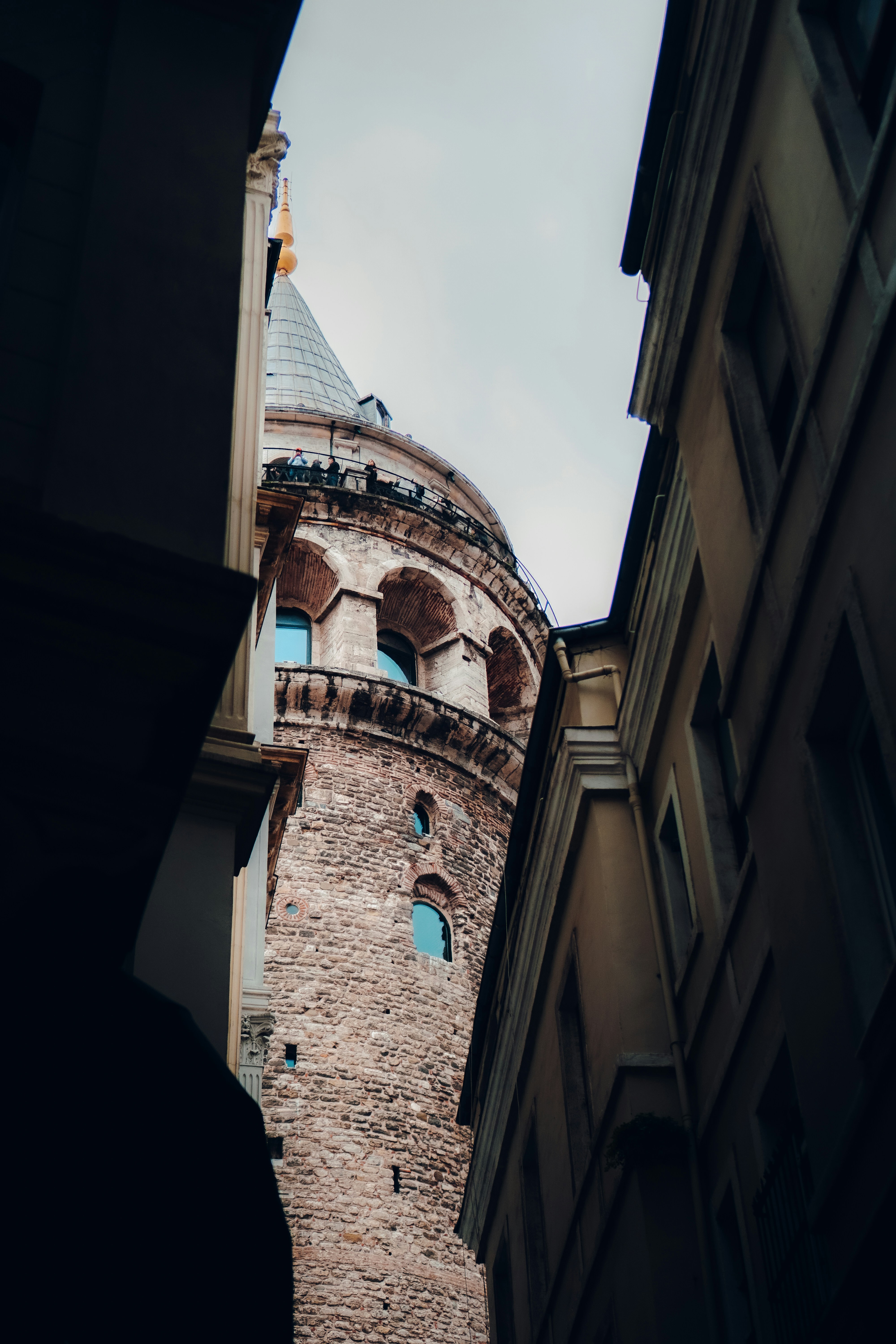 Historic stone tower framed by narrow alleyway, showcasing architectural details and a glimpse of the sky above.