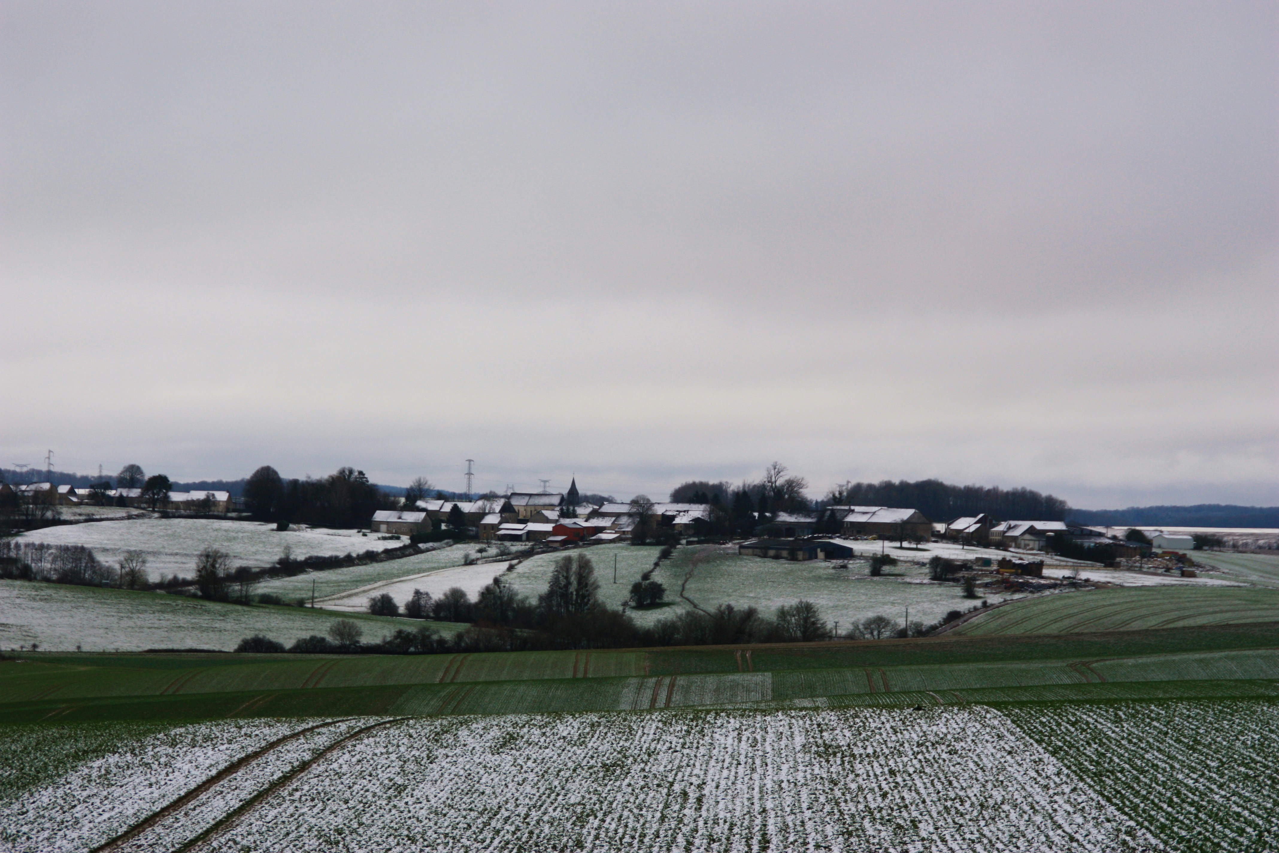 A snow covered field with a small town in the distance photo – Free ...