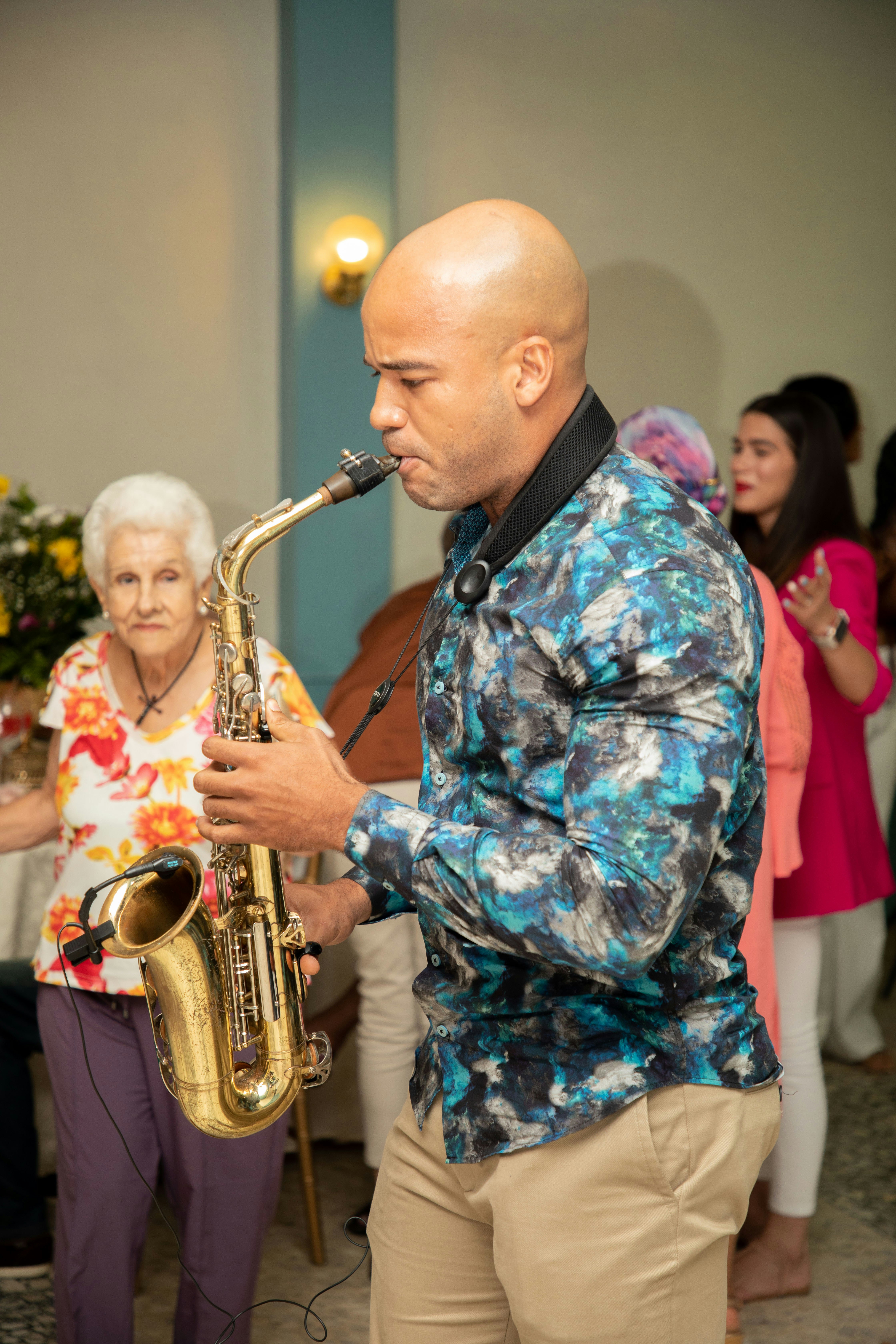 A man playing a saxophone in front of a group of people photo – Free ...