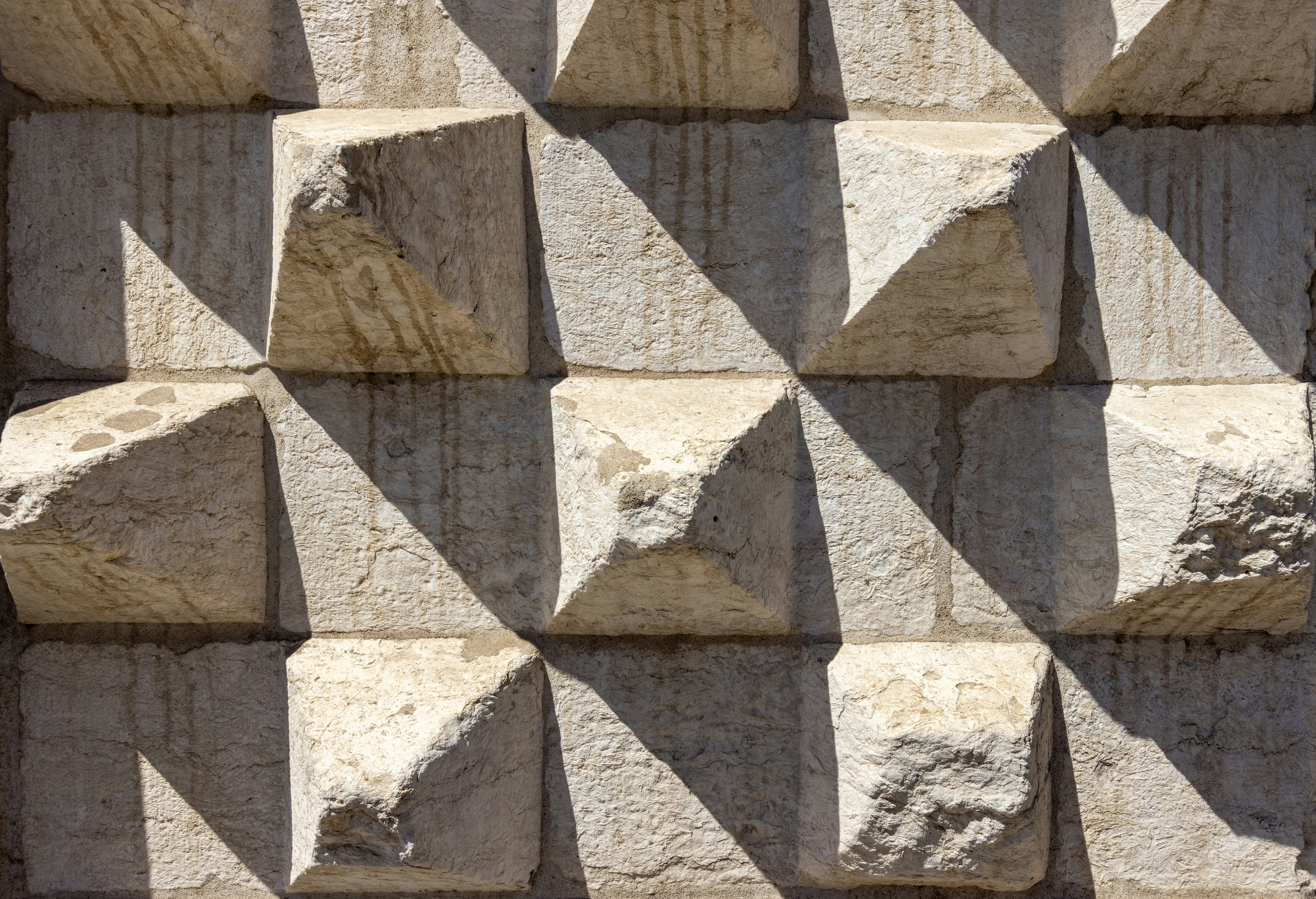 Sunlit Facets: Recessed Pyramid Grid on Weathered Stone