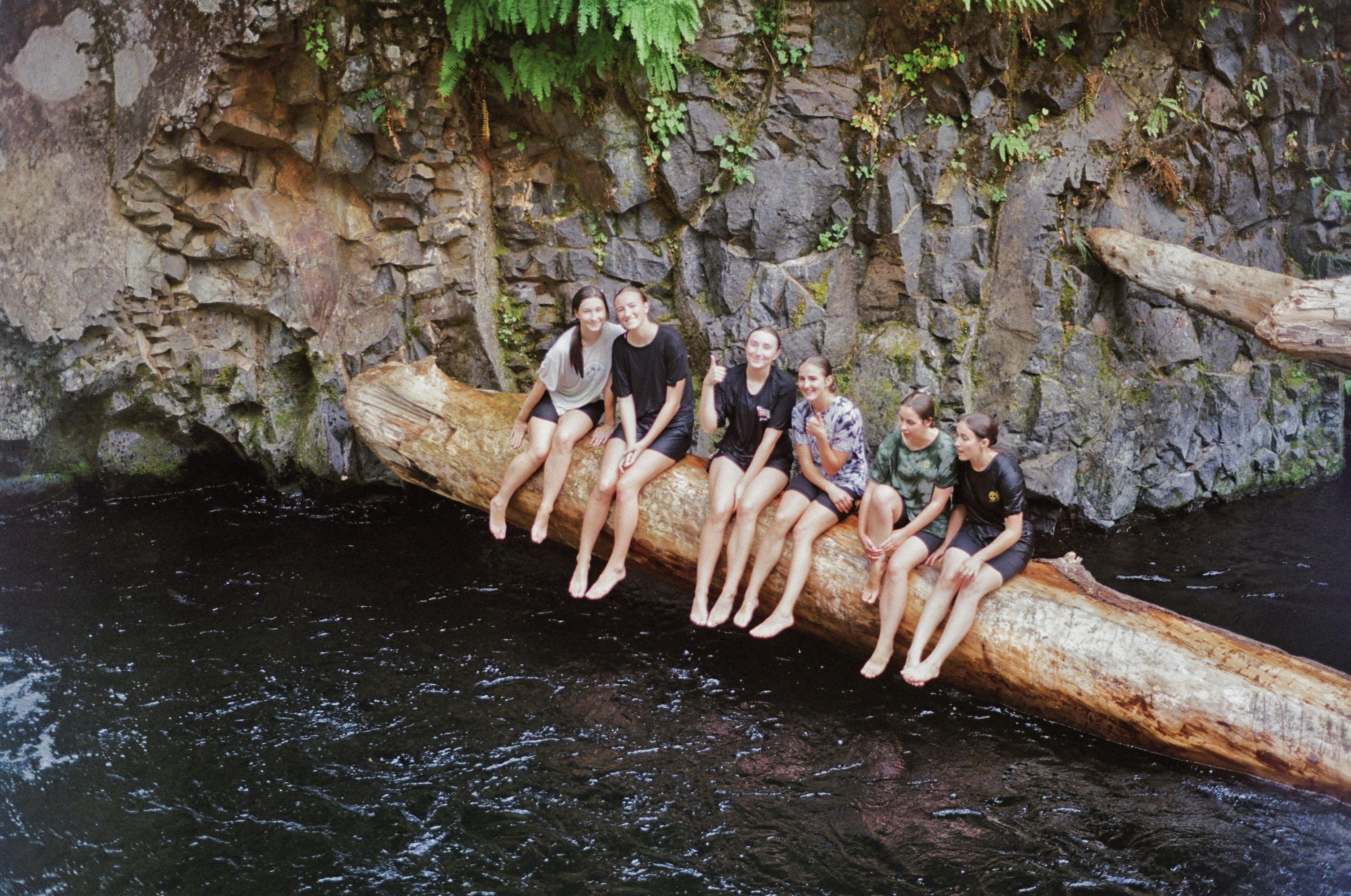 A group of people sitting on a log in a river photo – Free Outdoors ...