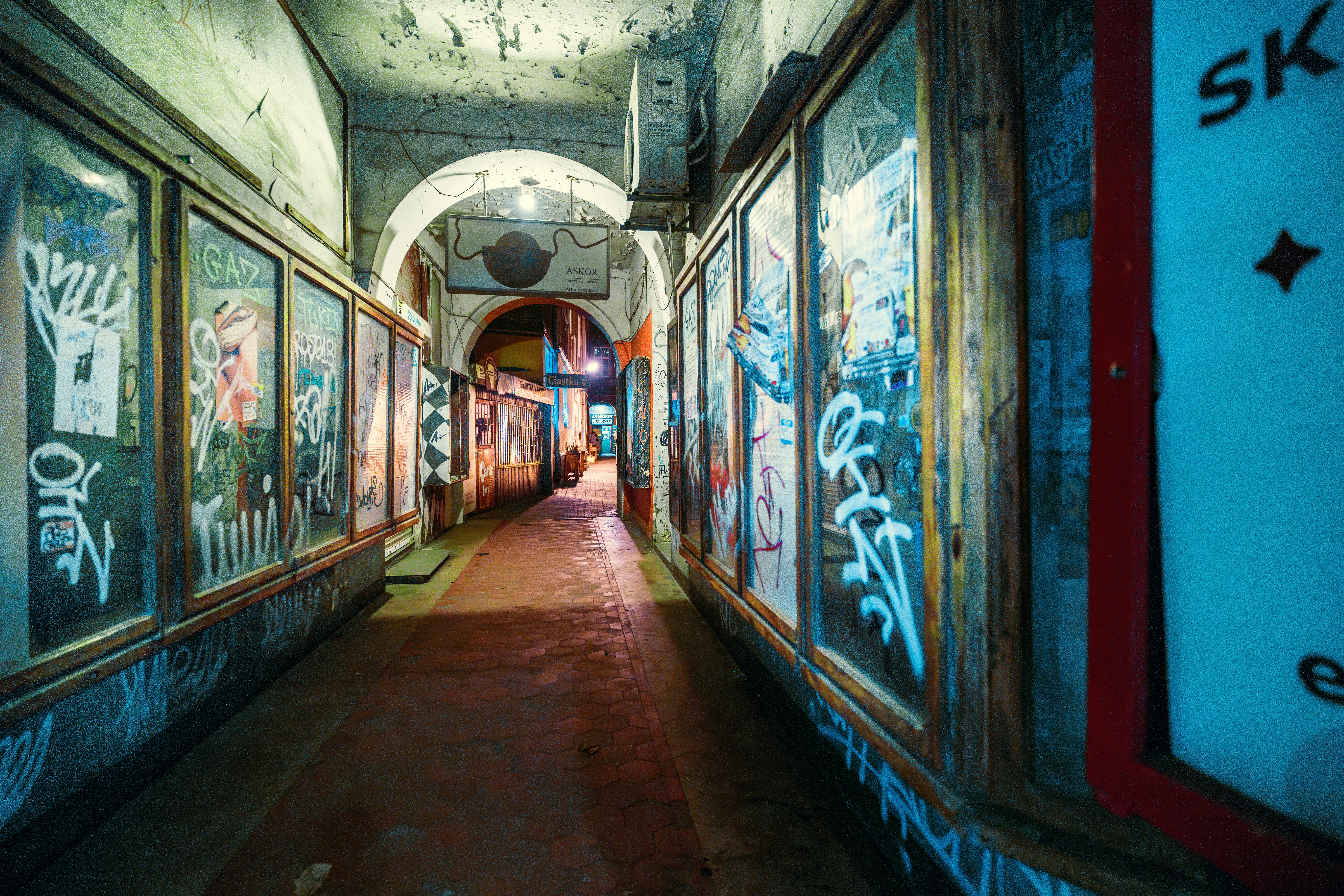 Blue Neon Corridor: Graffiti-Lined Alley Toward a Circular Arch