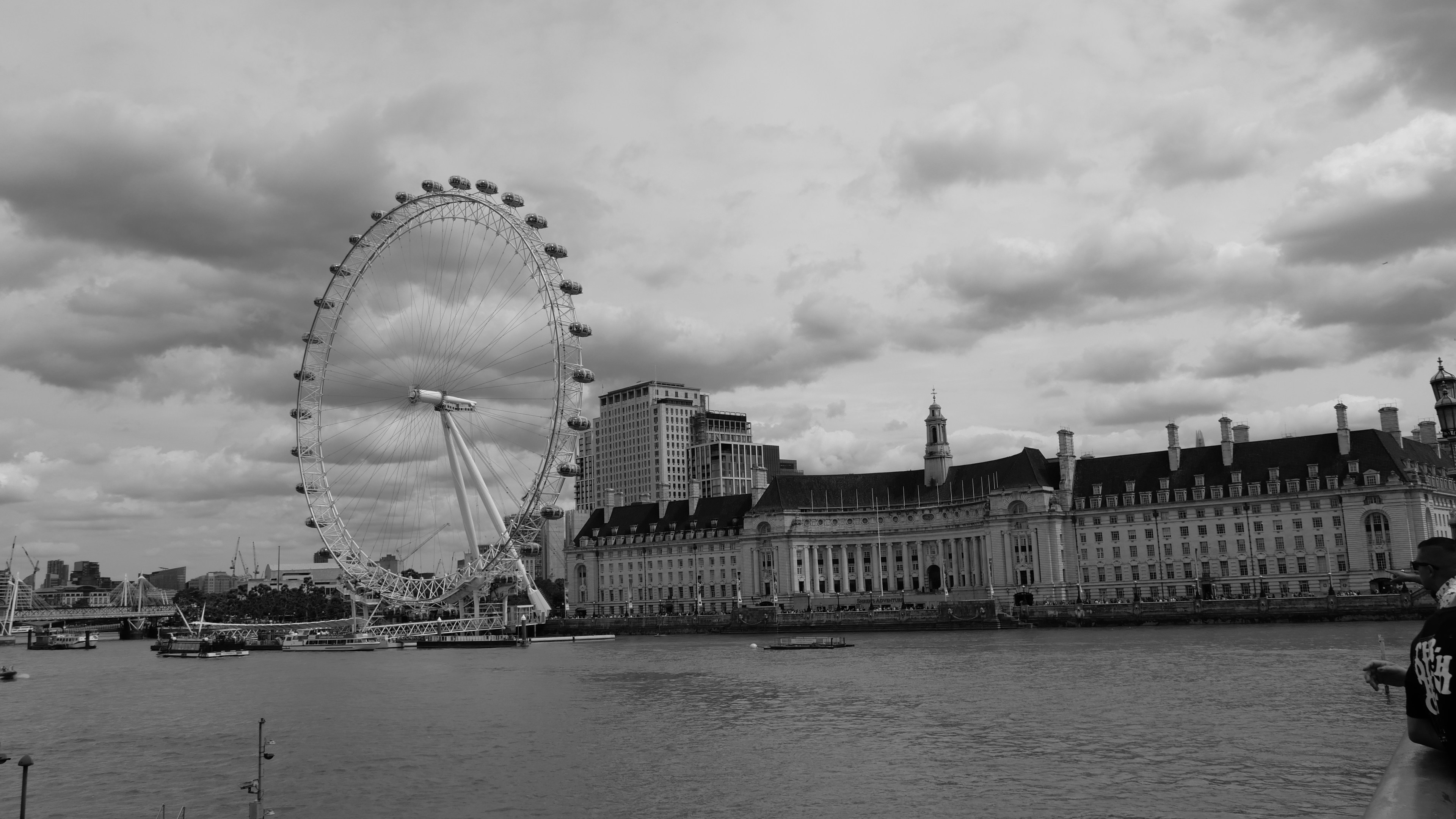 Iconic London Eye towering over the River Thames, framed by historic architecture and dramatic clouds.