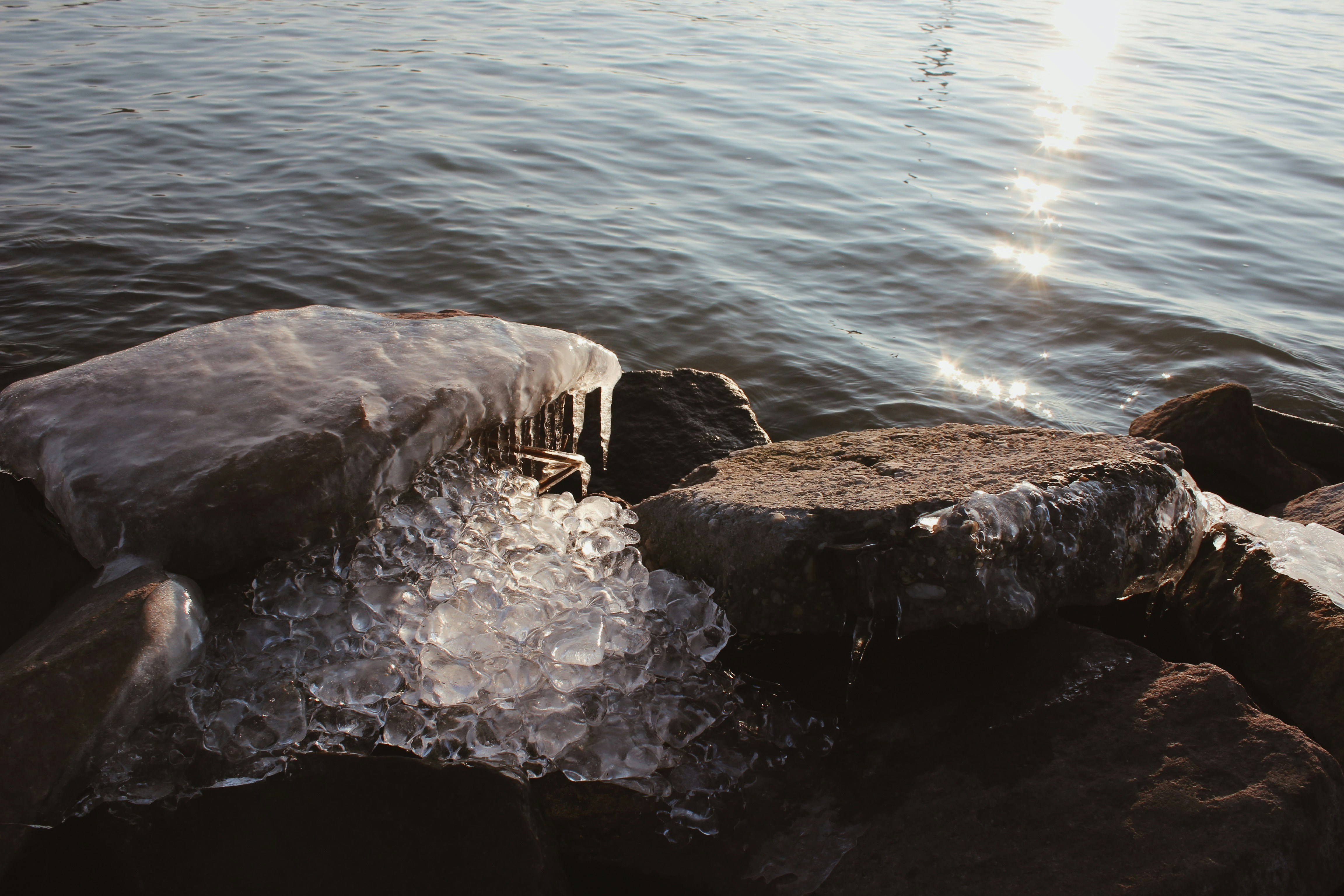 Ice on the Rocks at Dusk: Sunlit Ripples by a Quiet Shore