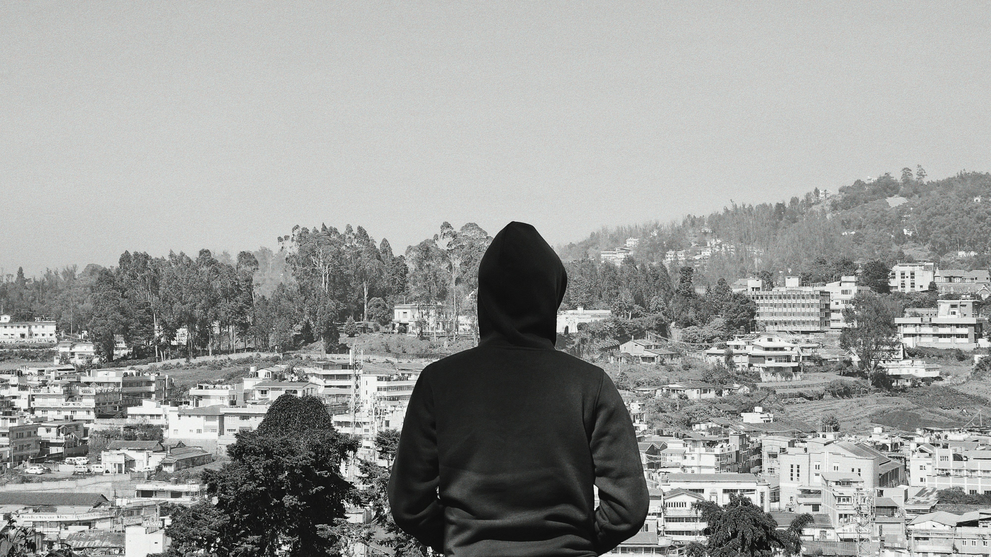 Hooded silhouette overlooking a hillside town