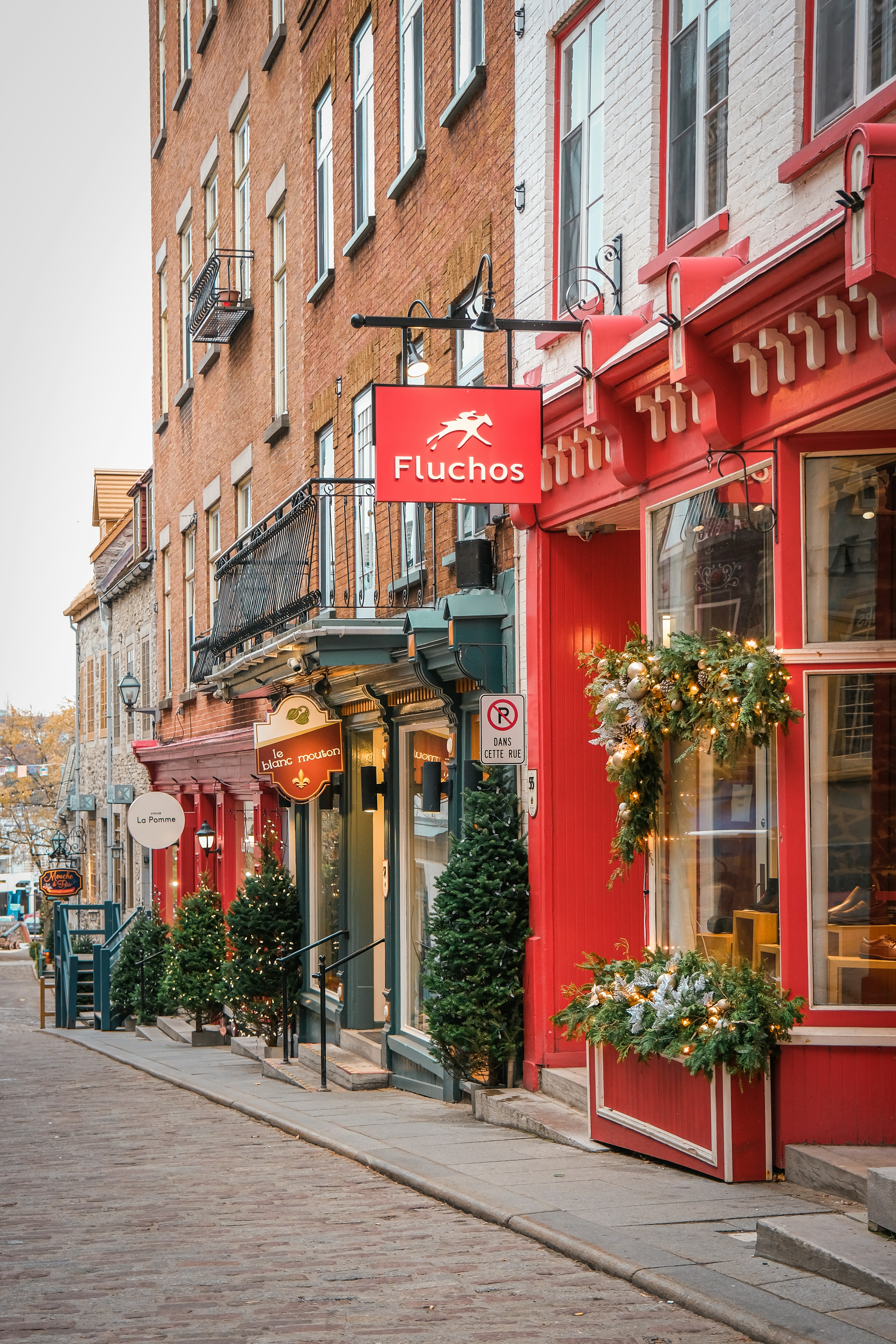 Red Facades and Festive Greens on a Cobbled City Lane