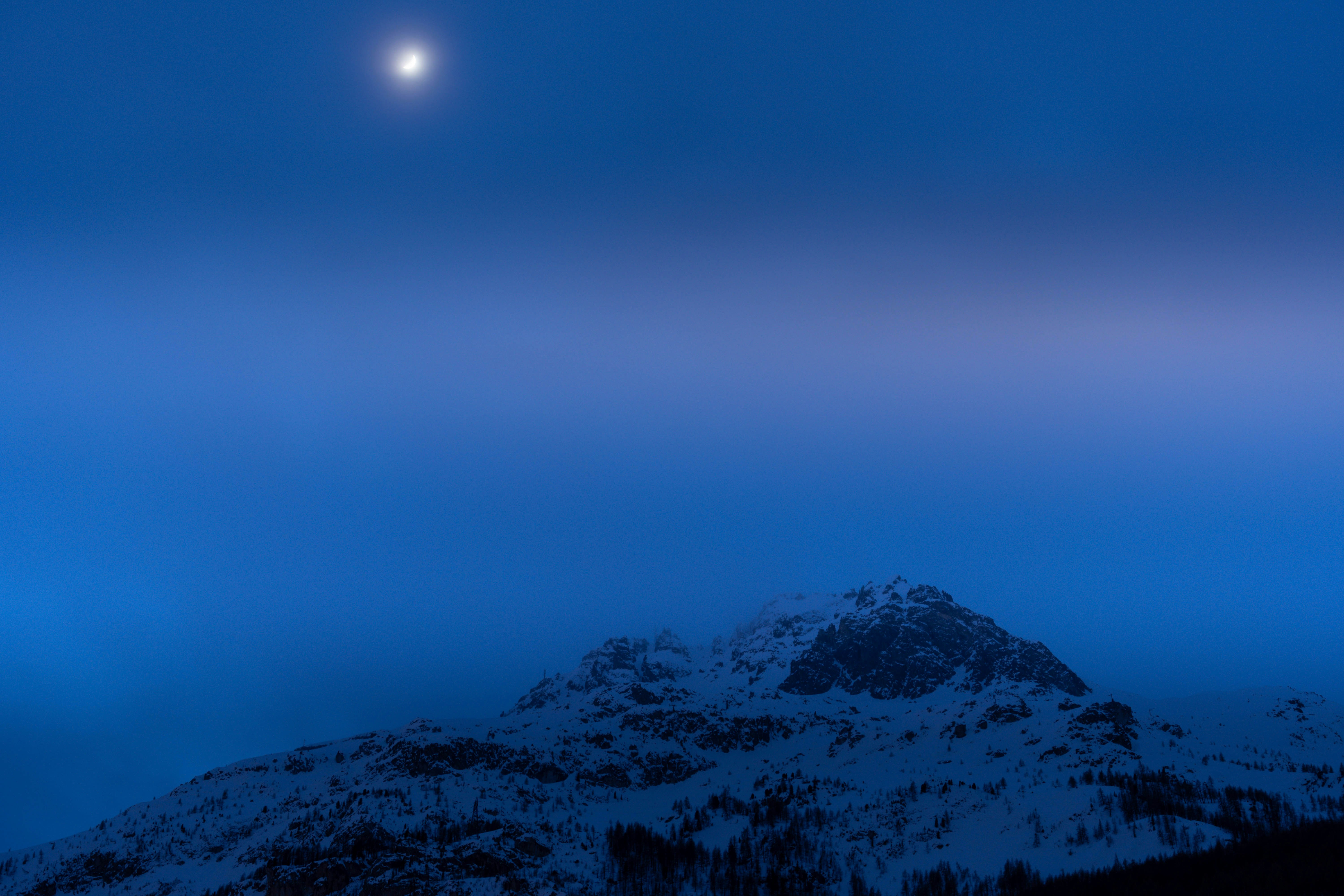 Cobalt Crest: Moon Above a Snowbound Ridge