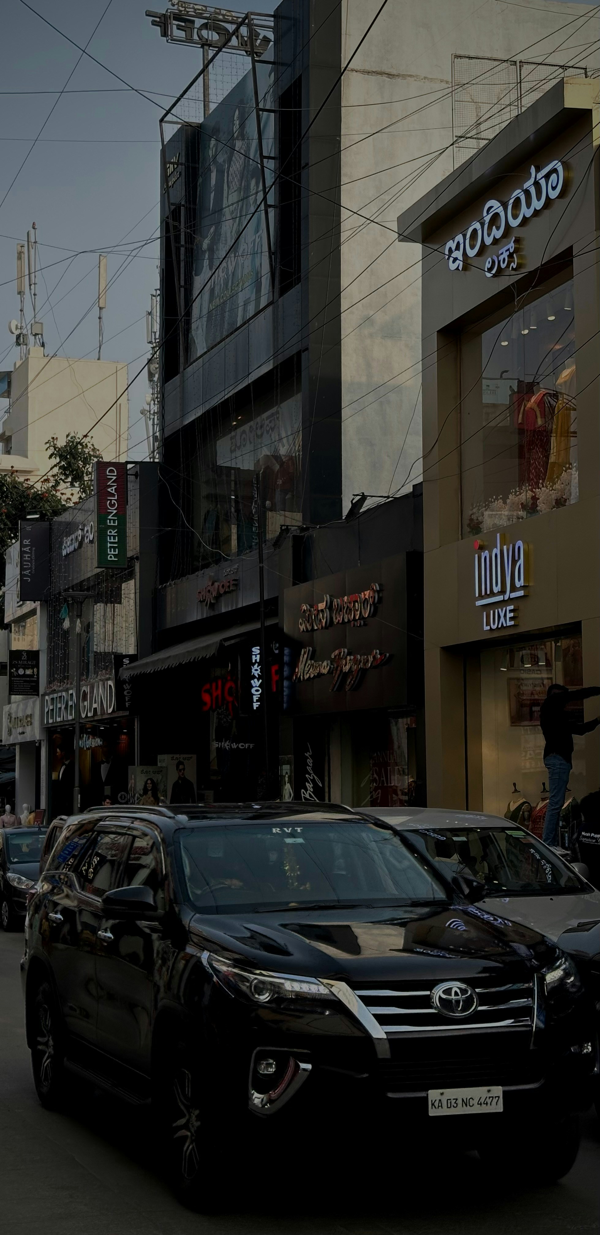Streetfront Pulse: A Black SUV Stands Sentry Amid a Boutique Row