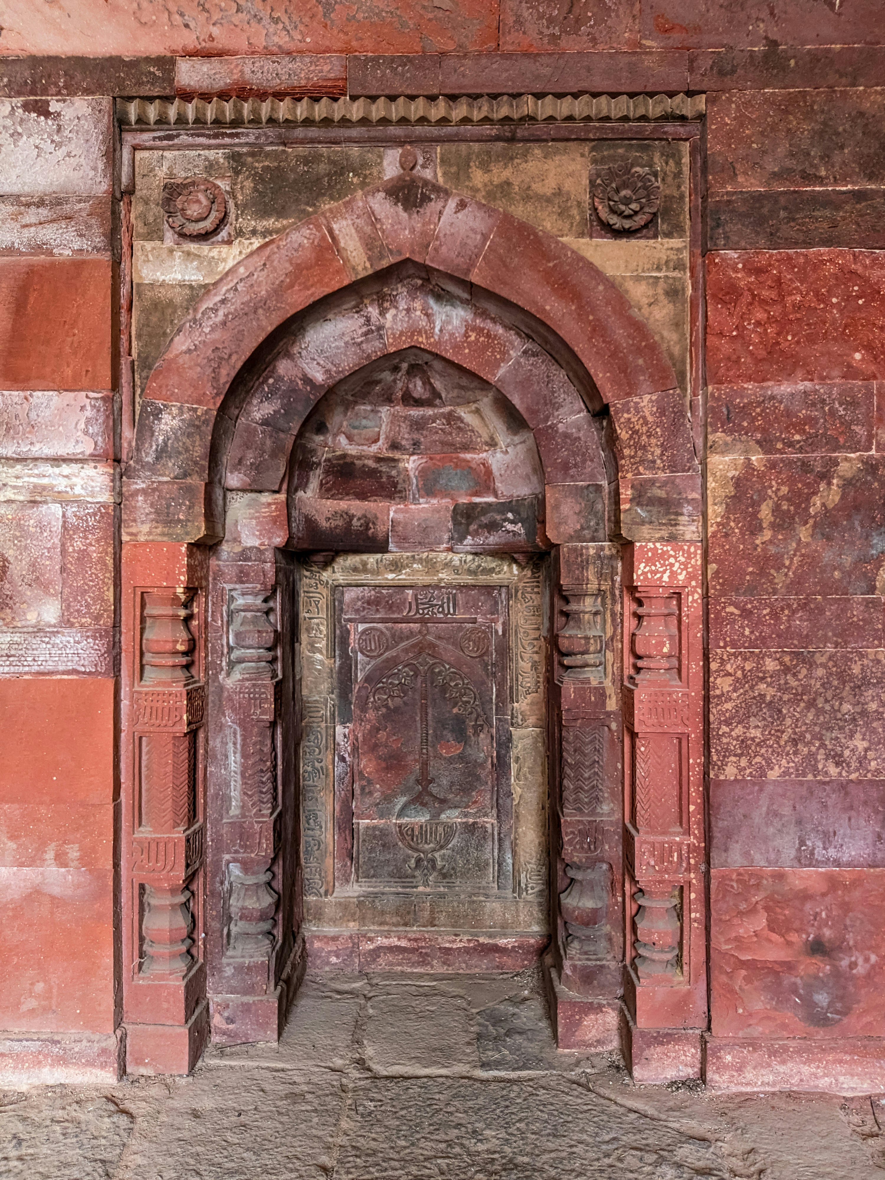 Archway of Time: Carved Red Sandstone Doorway in Weathered Temple Facade