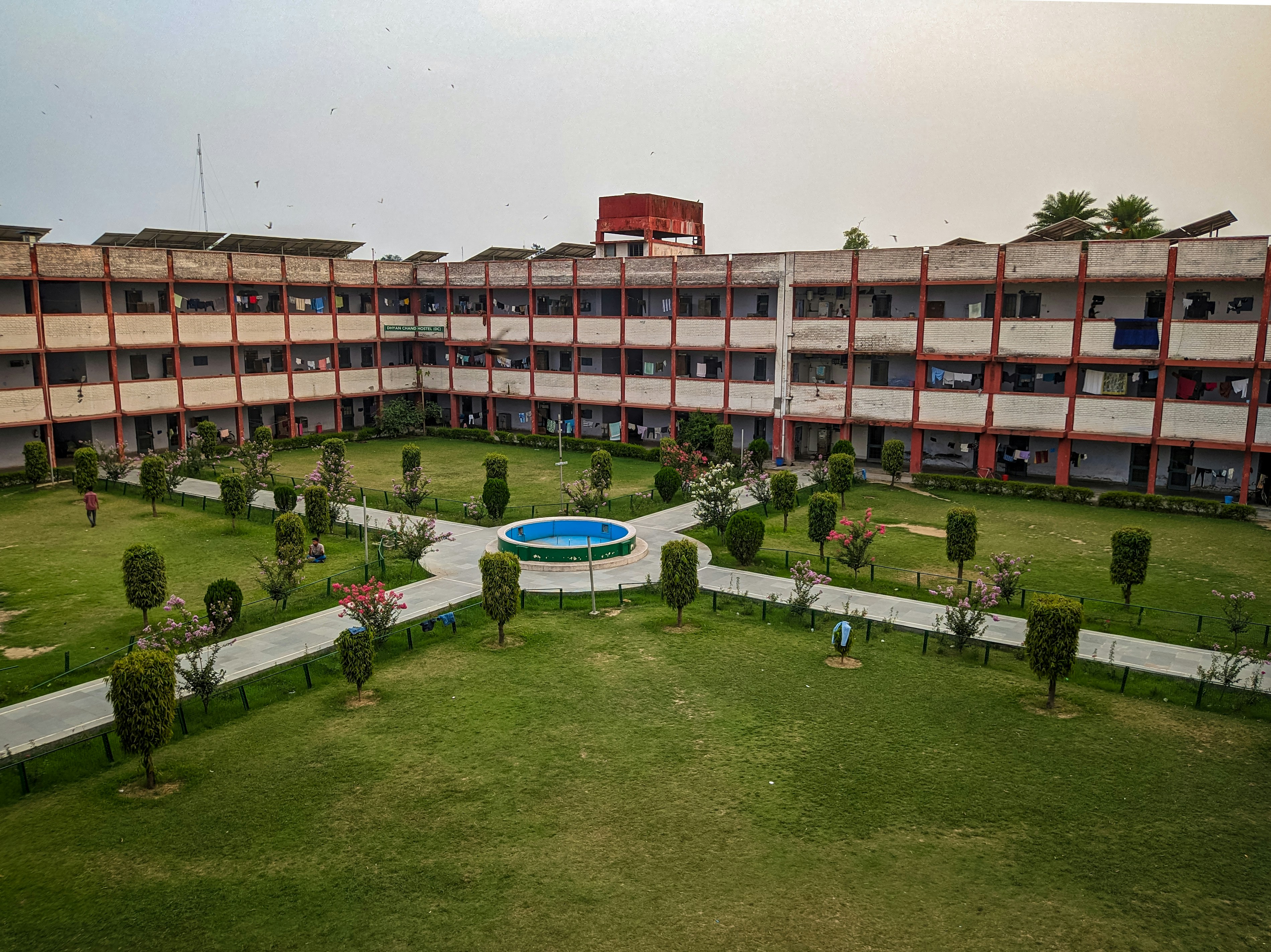Symmetrical courtyard with manicured lawns and a central fountain surrounded by a multi-story building.