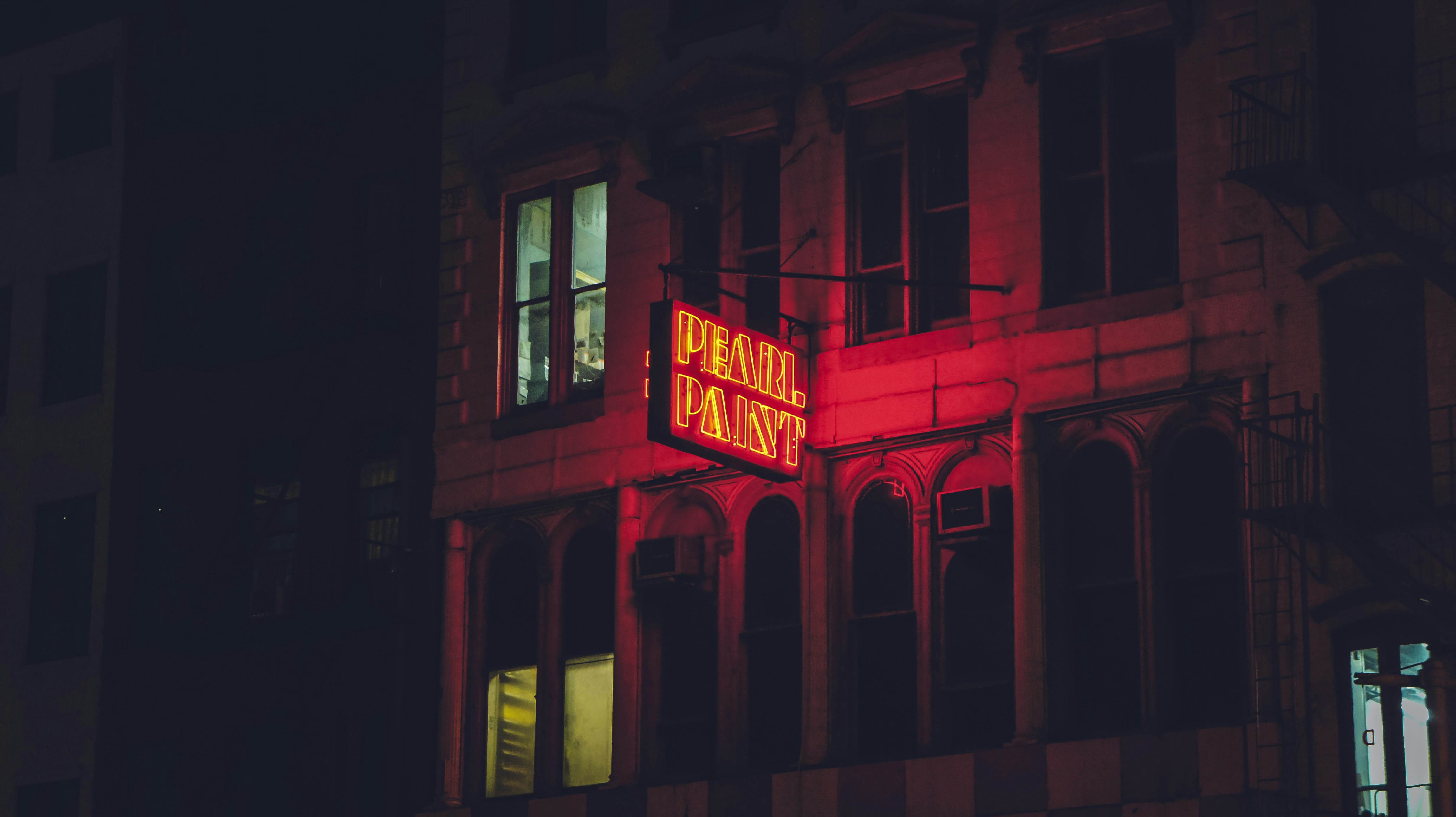 Neon Dream Paint Sign Illuminates a Brick Facade at Night