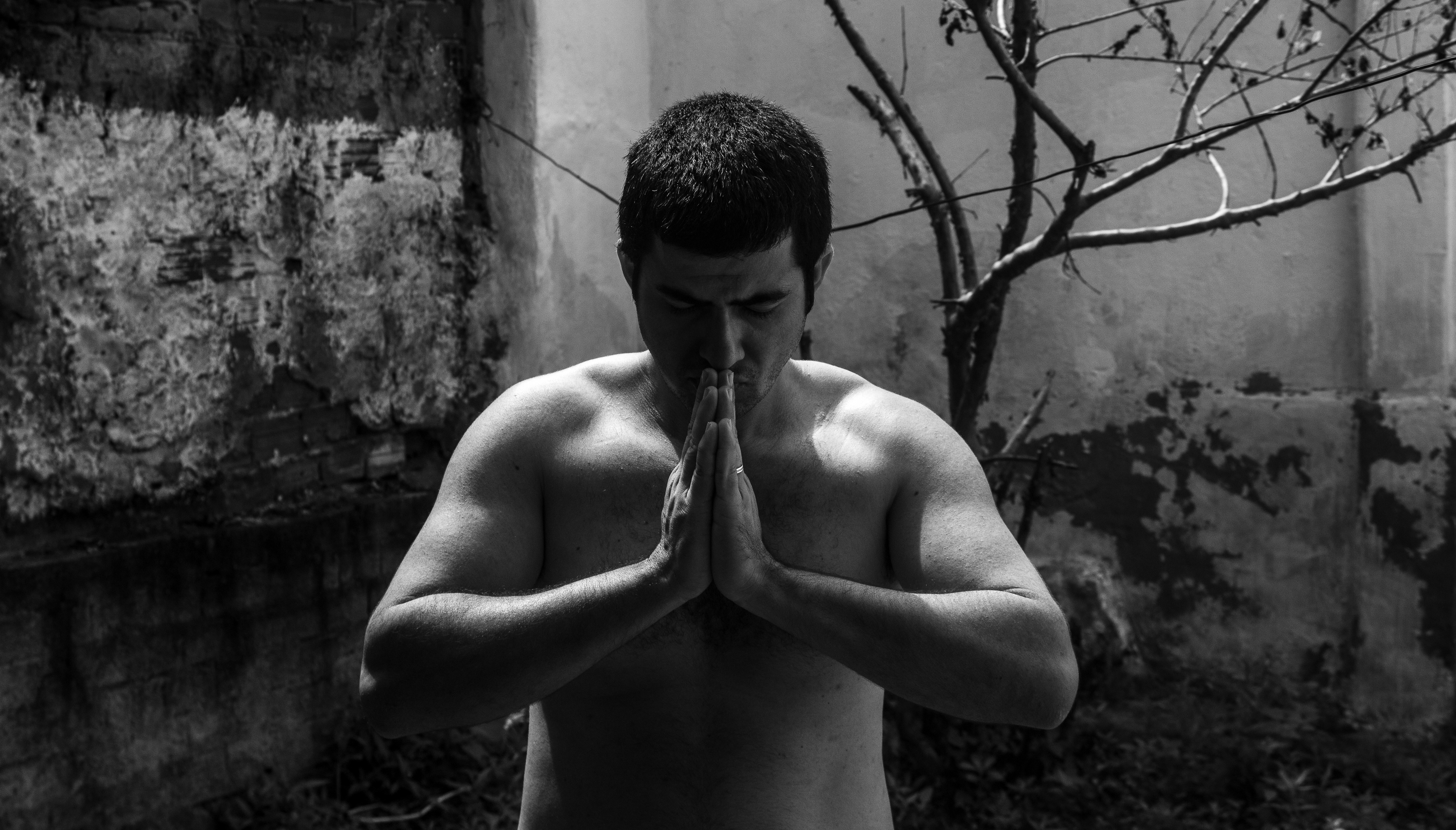 a shirtless man standing in front of a tree