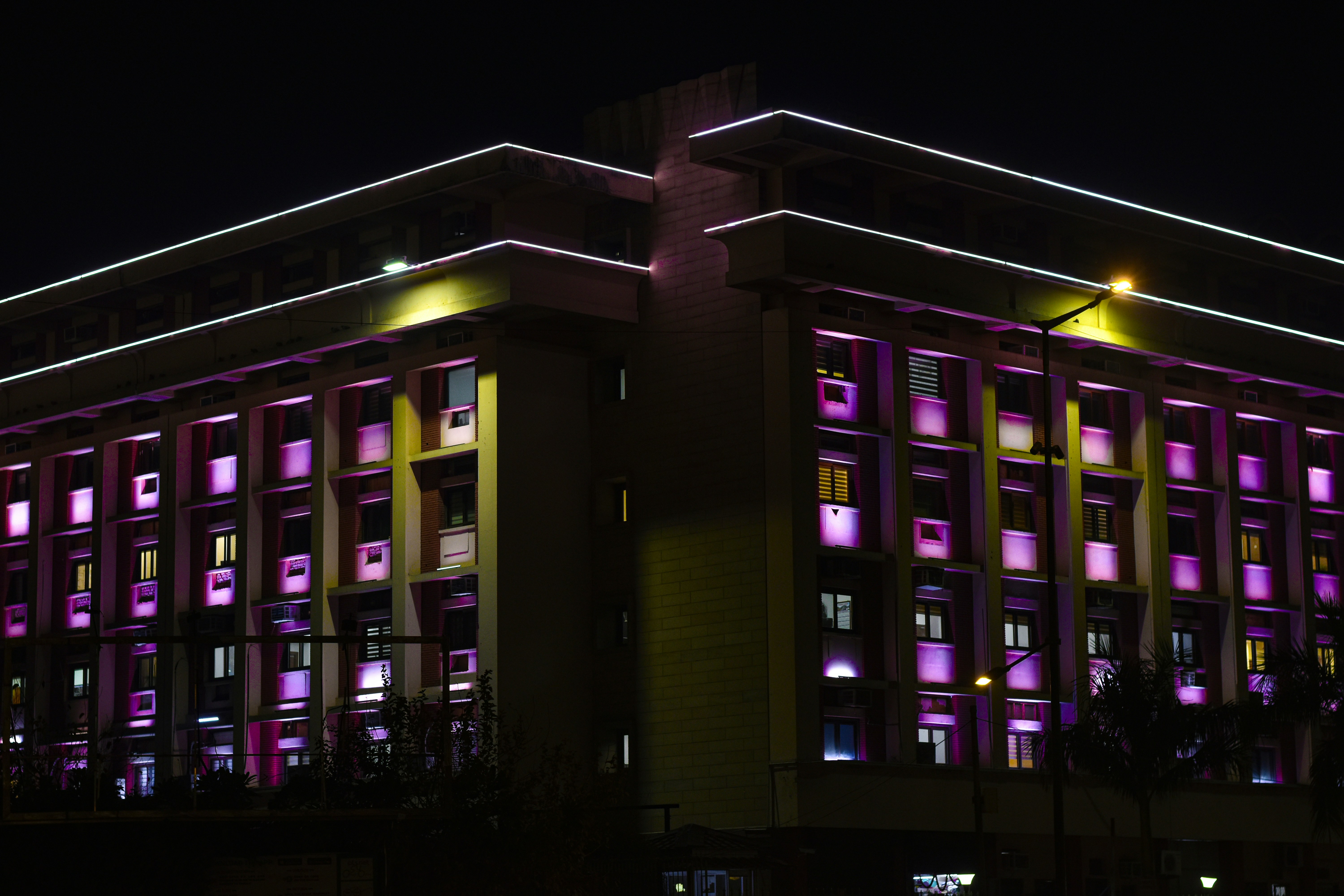 A large building lit up with purple lights photo – Free Rail bhavan ...