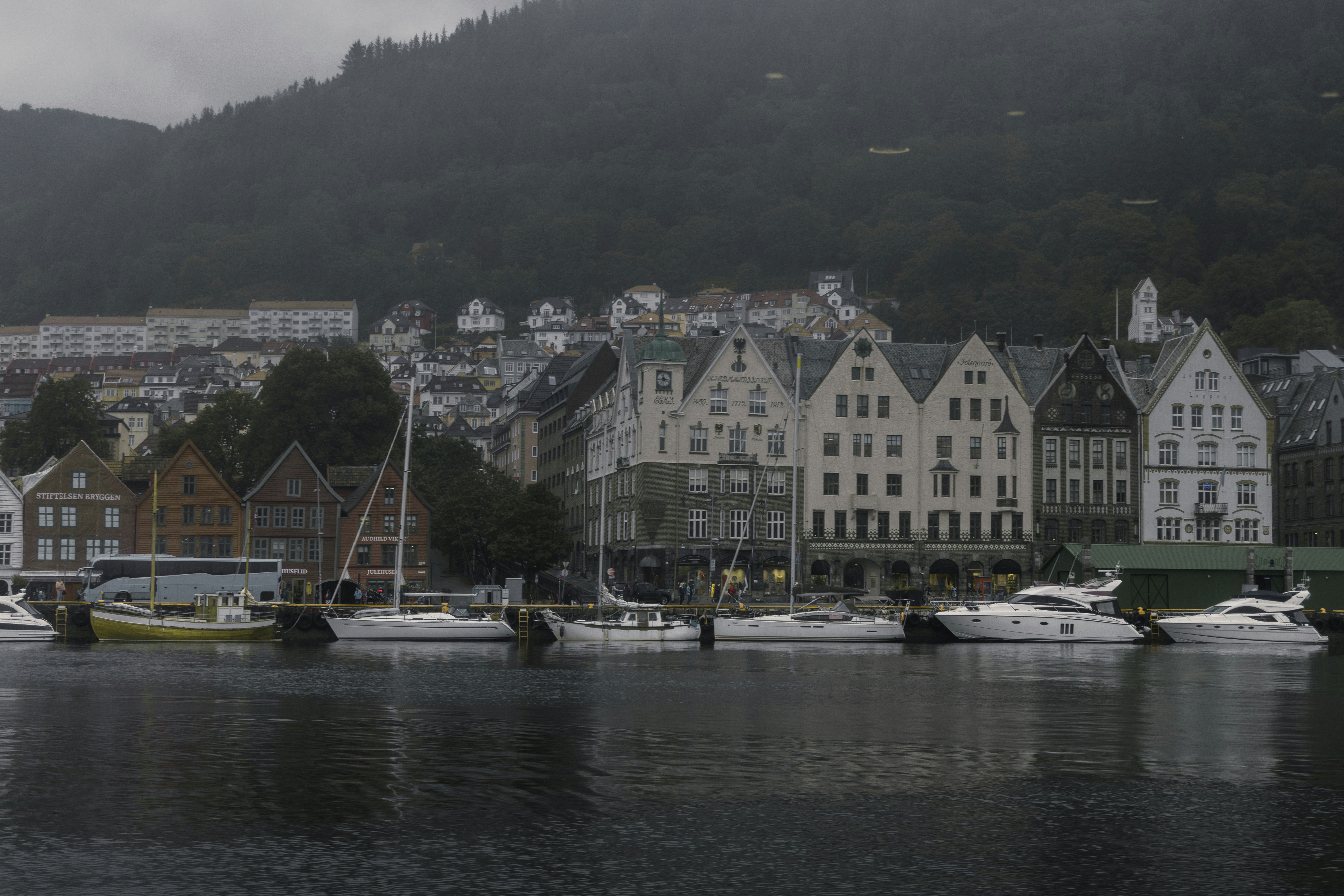 Harbor Row: Timbered Facades and Quiet Boats Beneath Clouded Hills