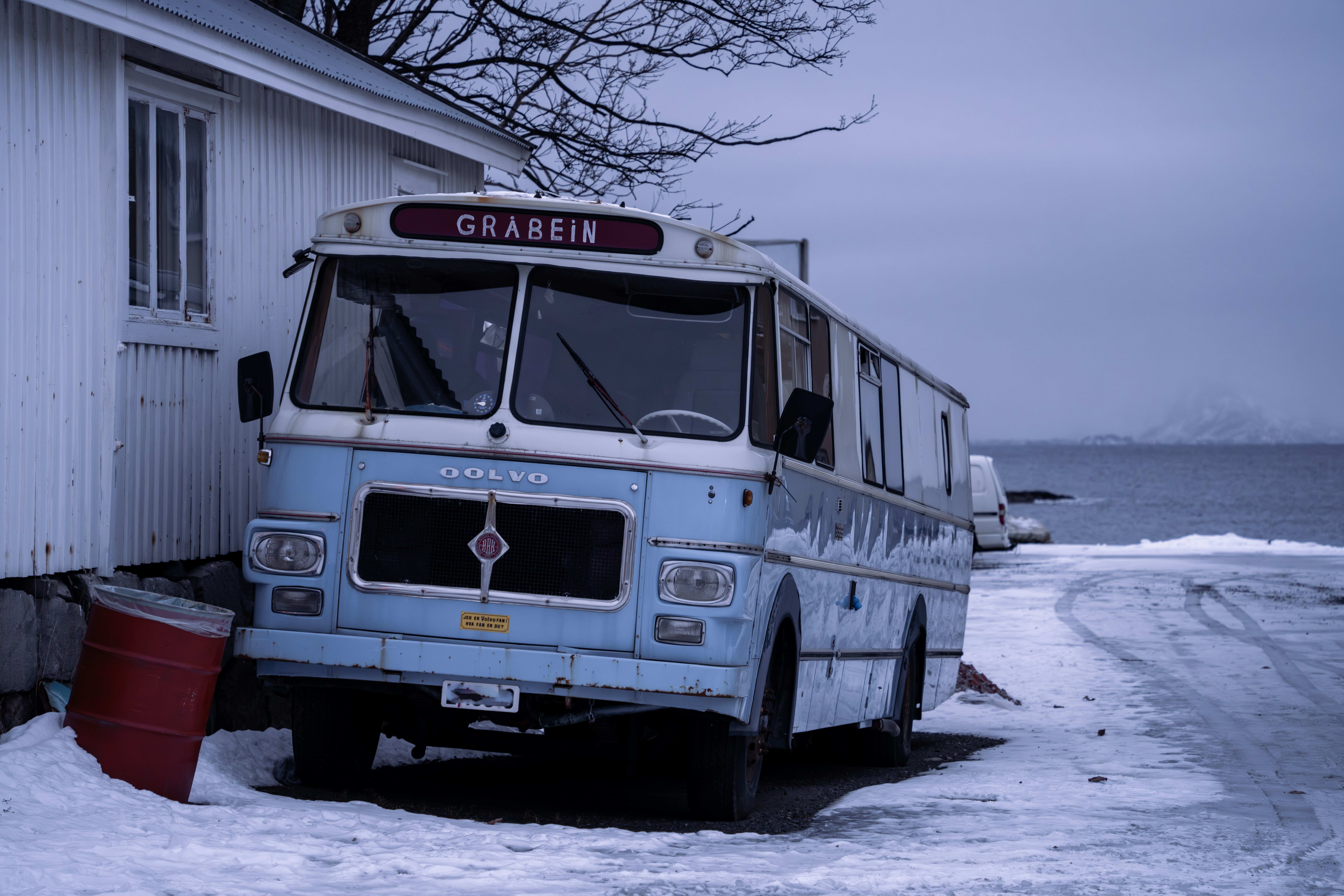 A blue bus parked in front of a white building photo – Free Henningsvær ...