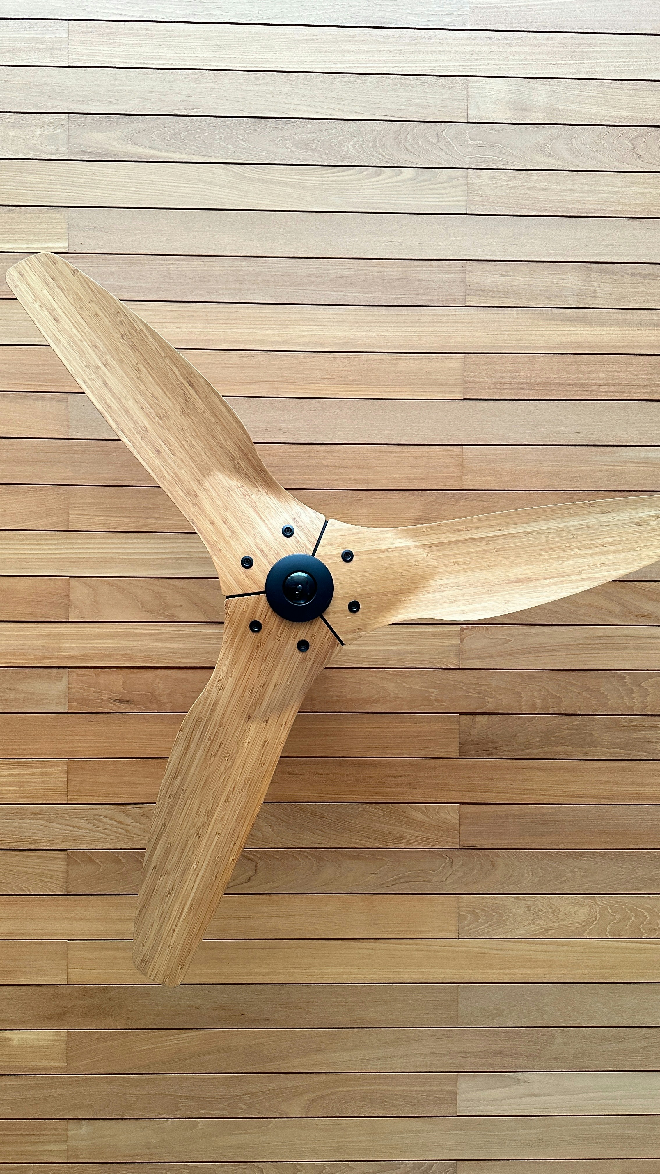 Overhead View of a Three-Blade Wooden Propeller on a Striped Hardwood Floor