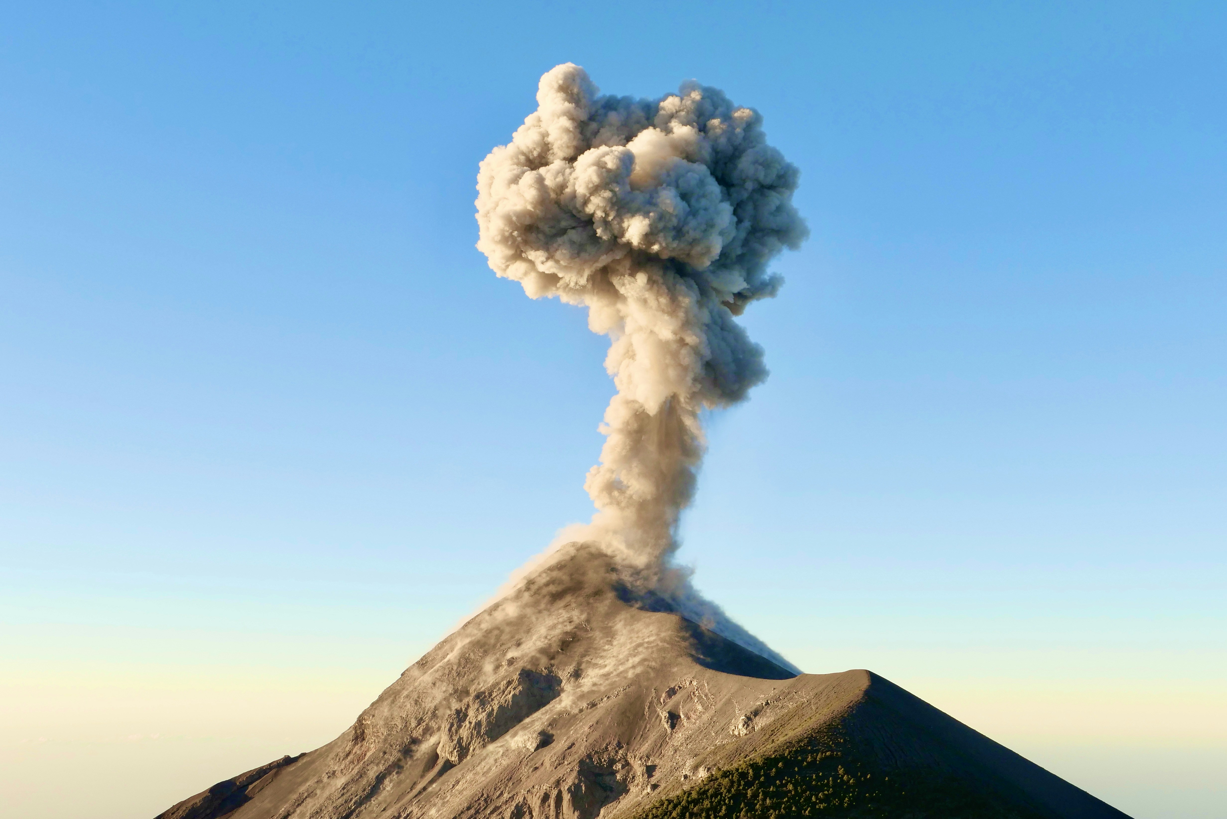 a large plume of smoke rising from the top of a mountain
