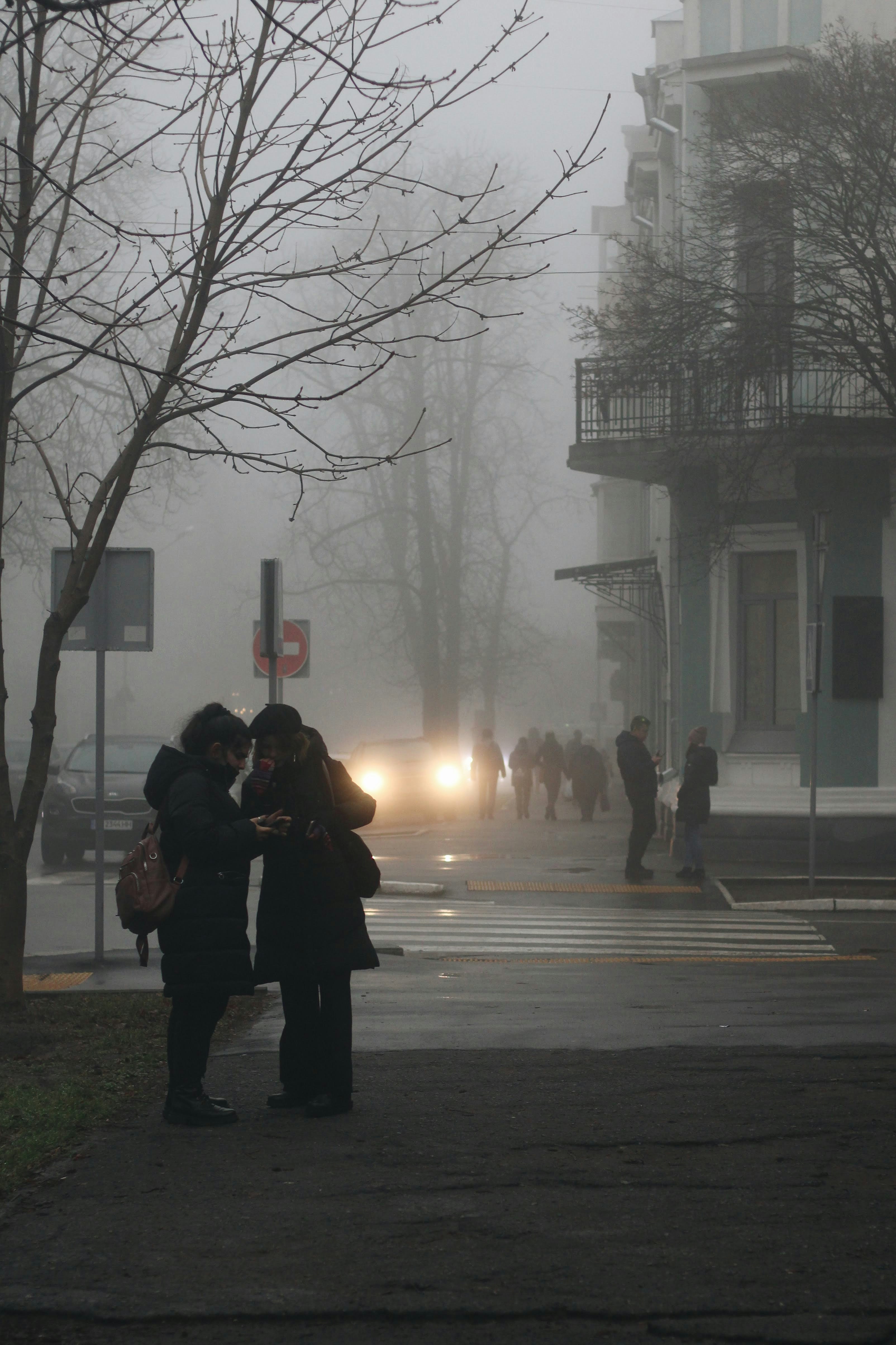 Veiled Crossing: Two silhouettes in a foggy urban dusk