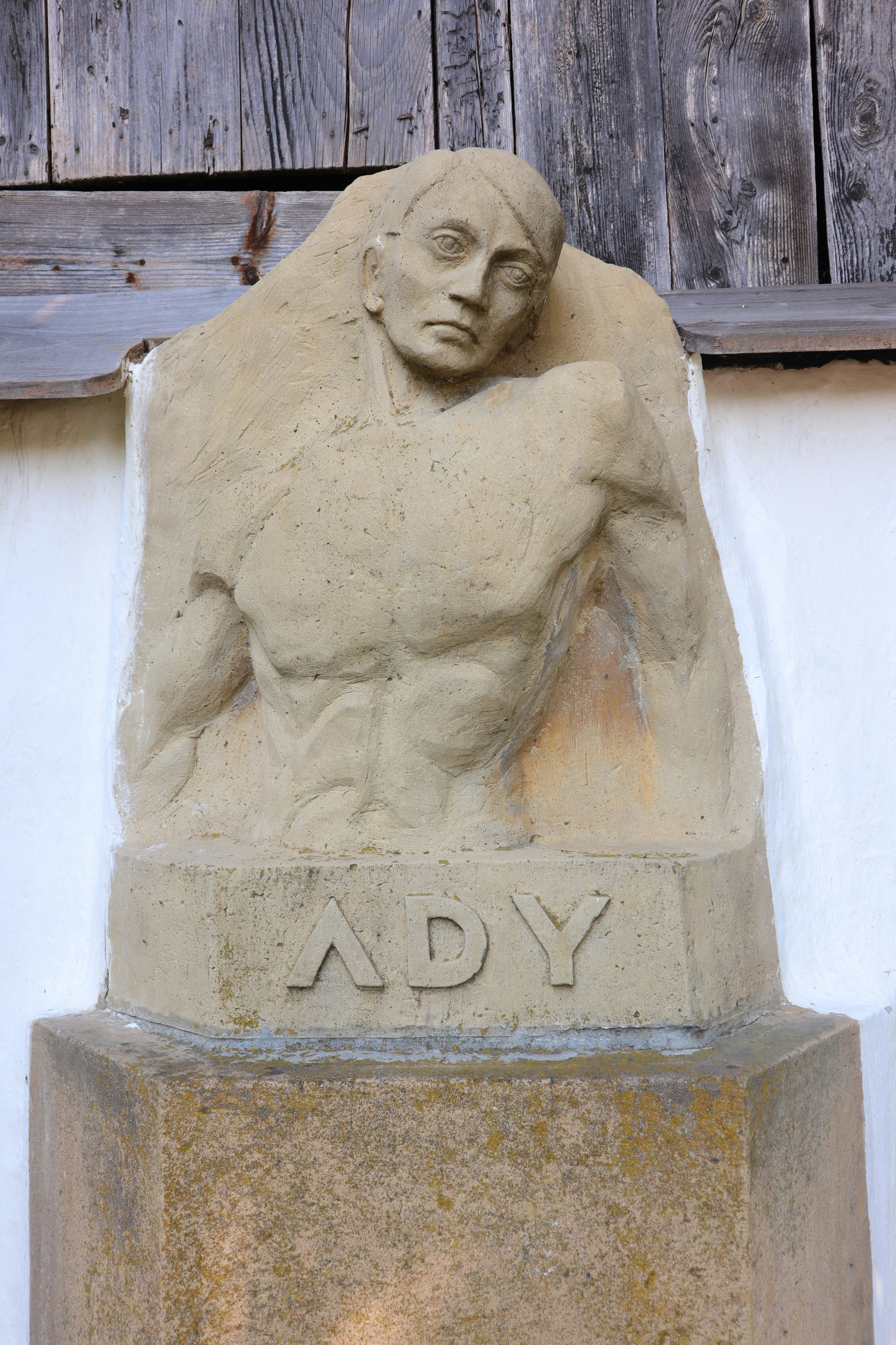 ADY in Sand: Weathered Bust Carved from Sand Against a Rustic Wood Backdrop
