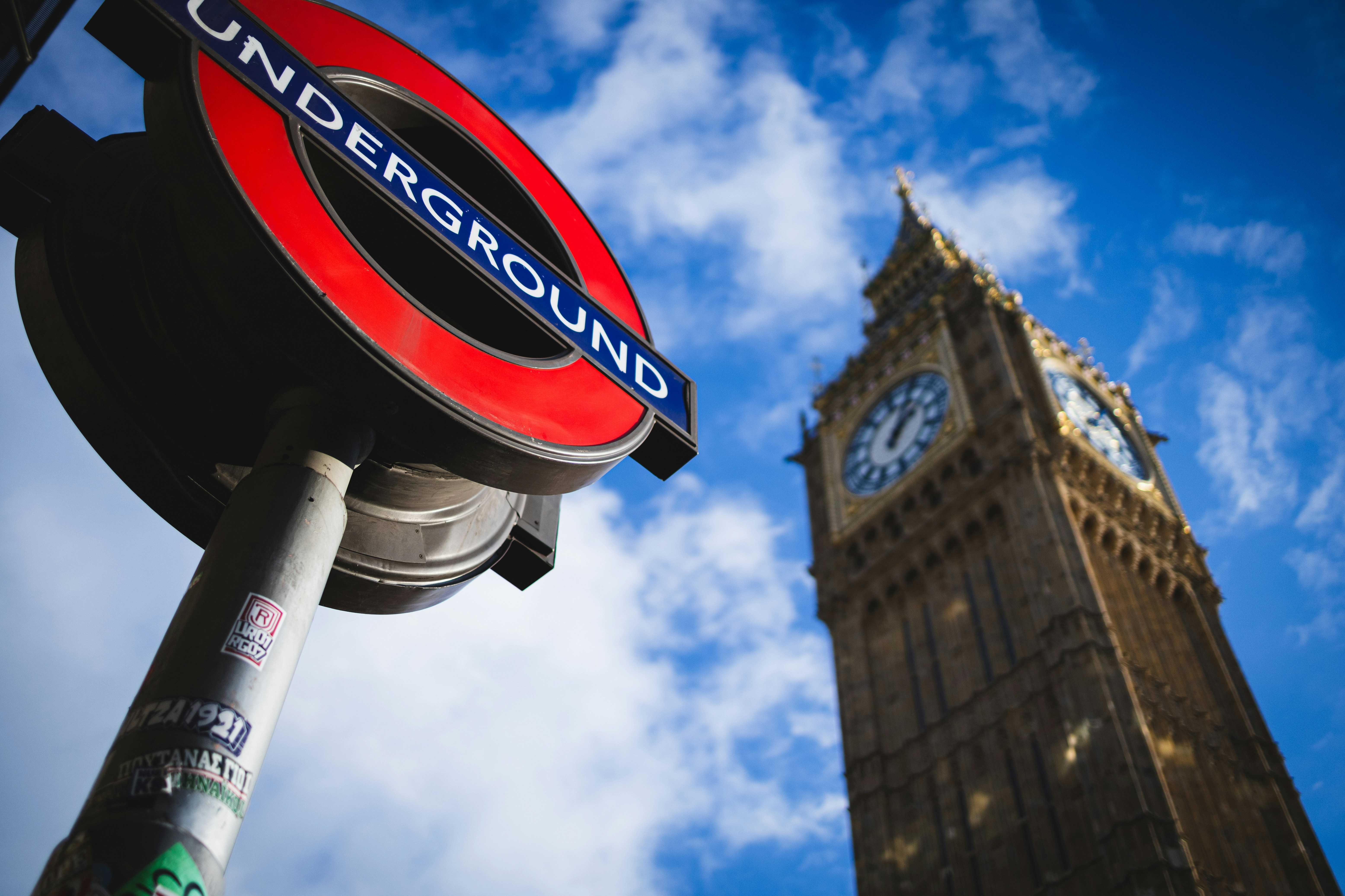 Roundel at Street Level: Underground Sign Framed by Big Ben under a Bright London Sky