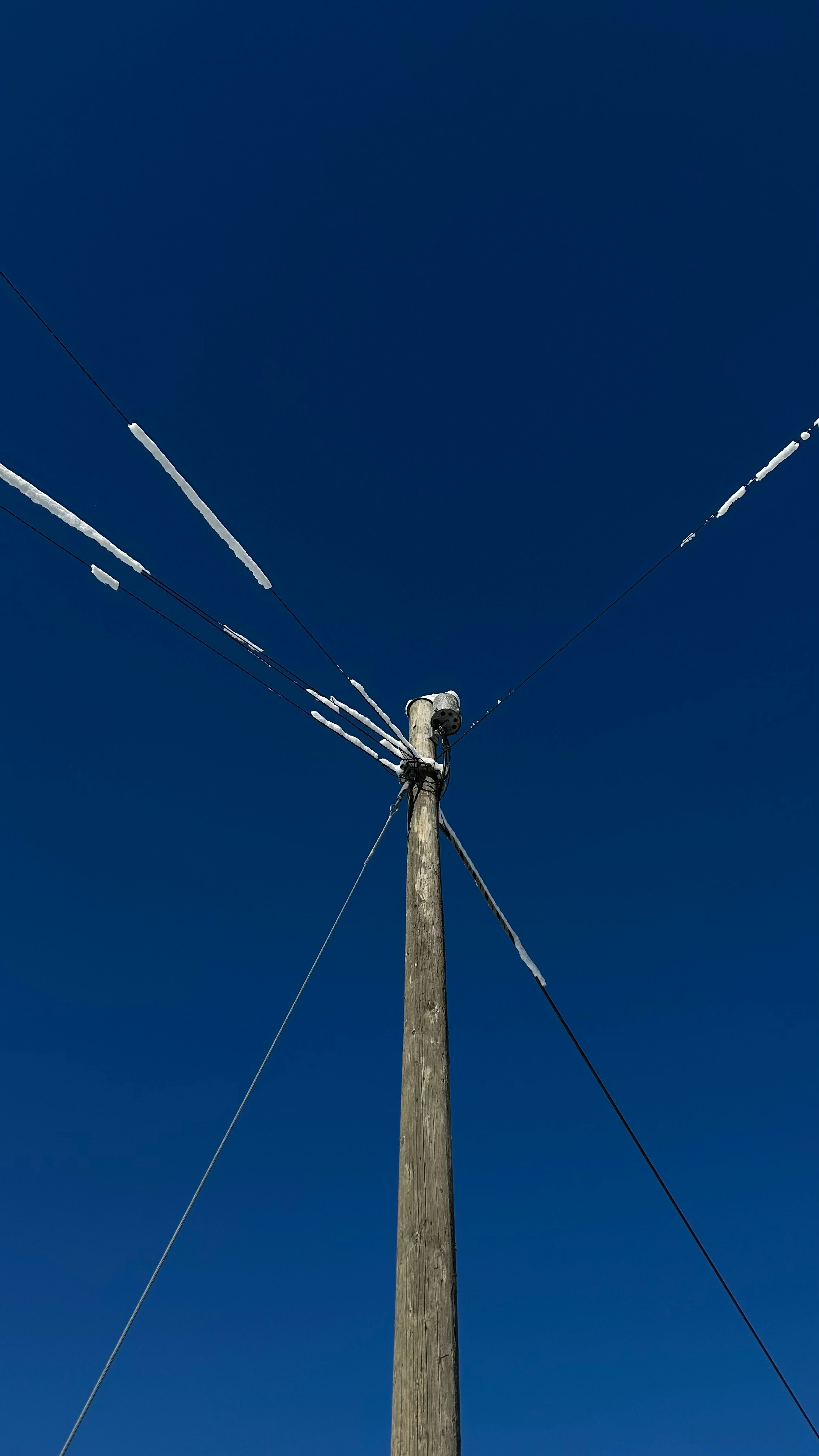 Pole Top Convergence: Wires Fan Out Across a Cerulean Sky