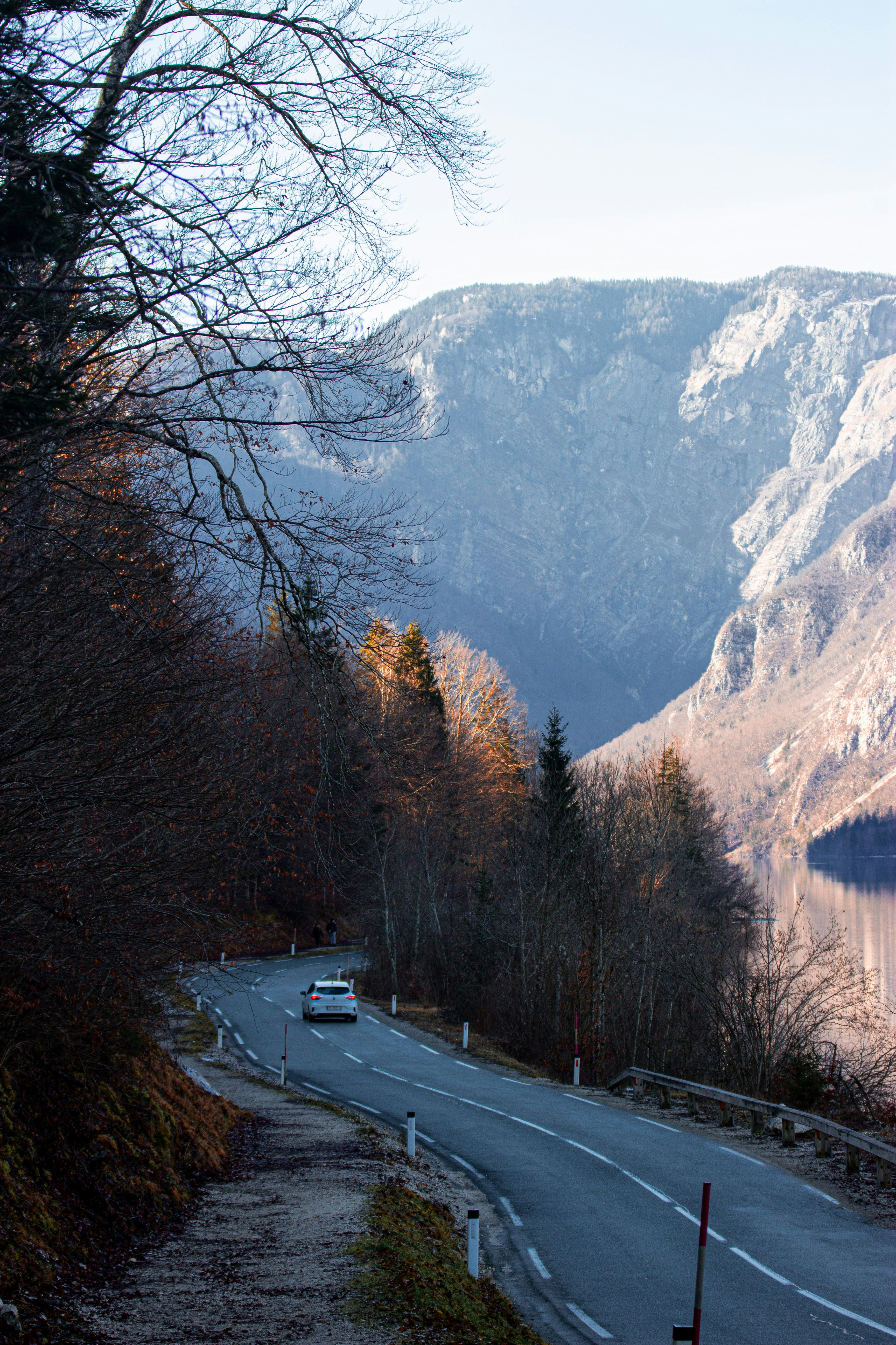 Winding Toward the Cliffline: Alpine Lakeside Road with a Solo Car