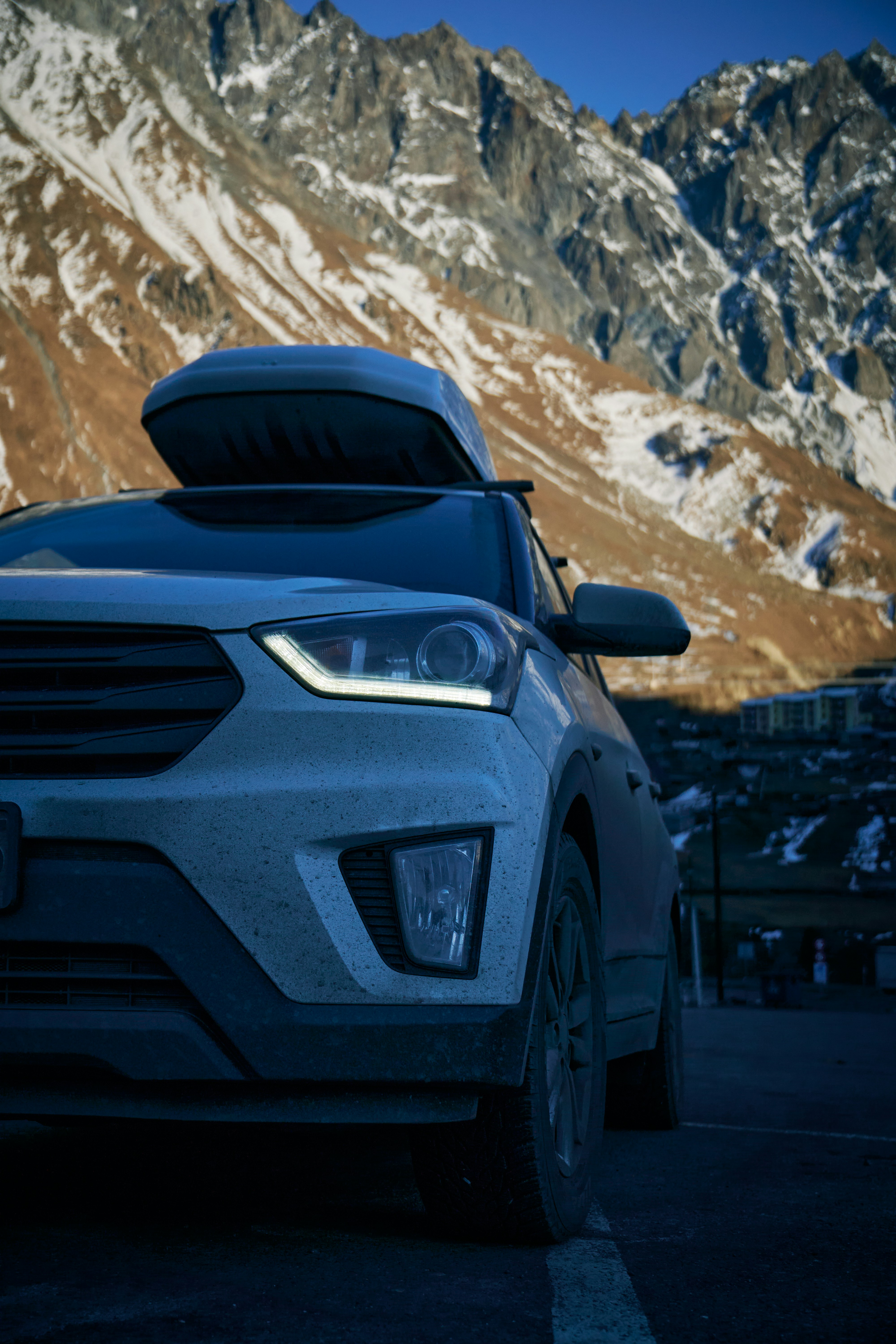 Alpine Approach: Front-Quarter Shot of a Snow-Dusted SUV Under Rugged Peaks
