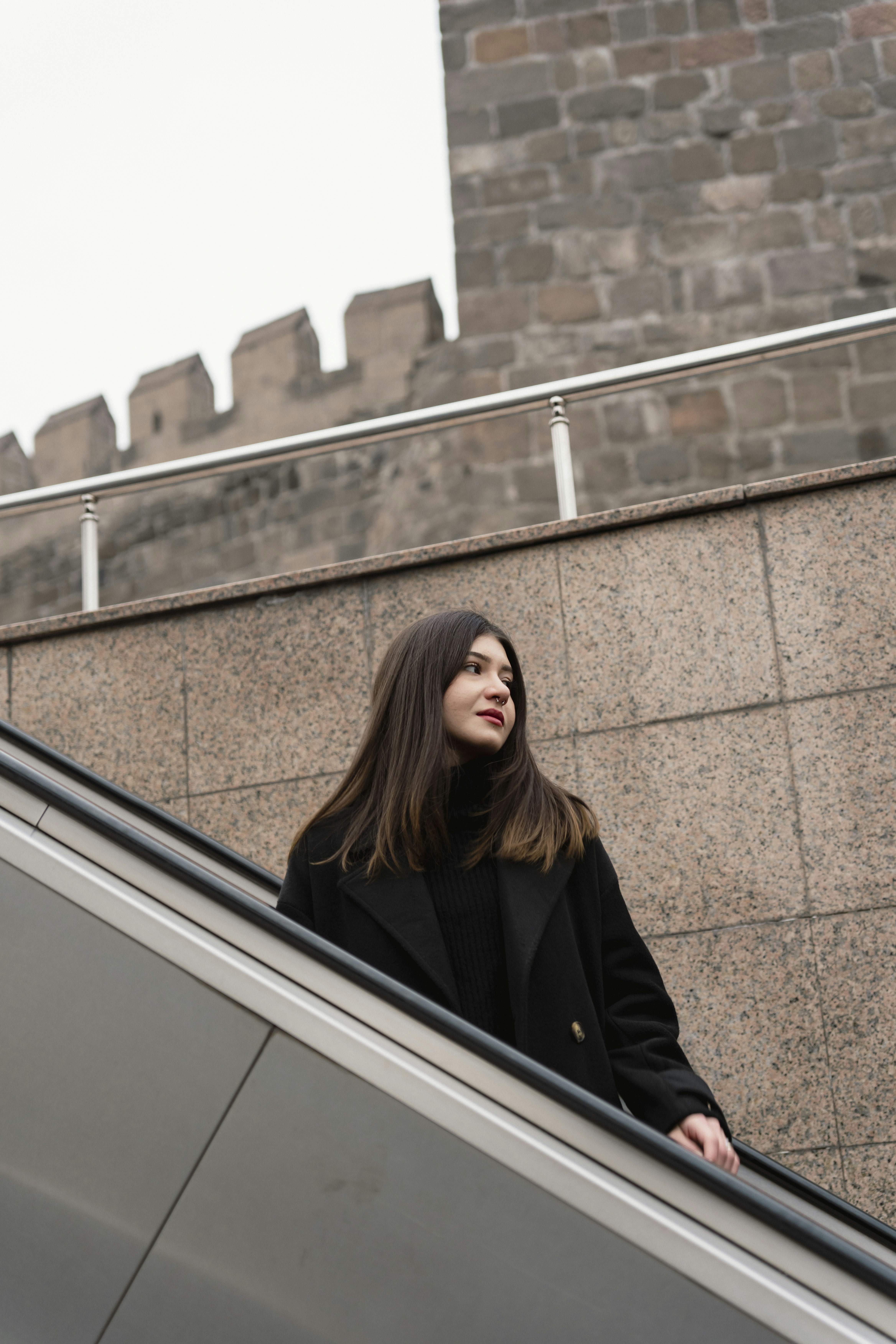 A woman standing on an escalator next to a building photo – Free ...