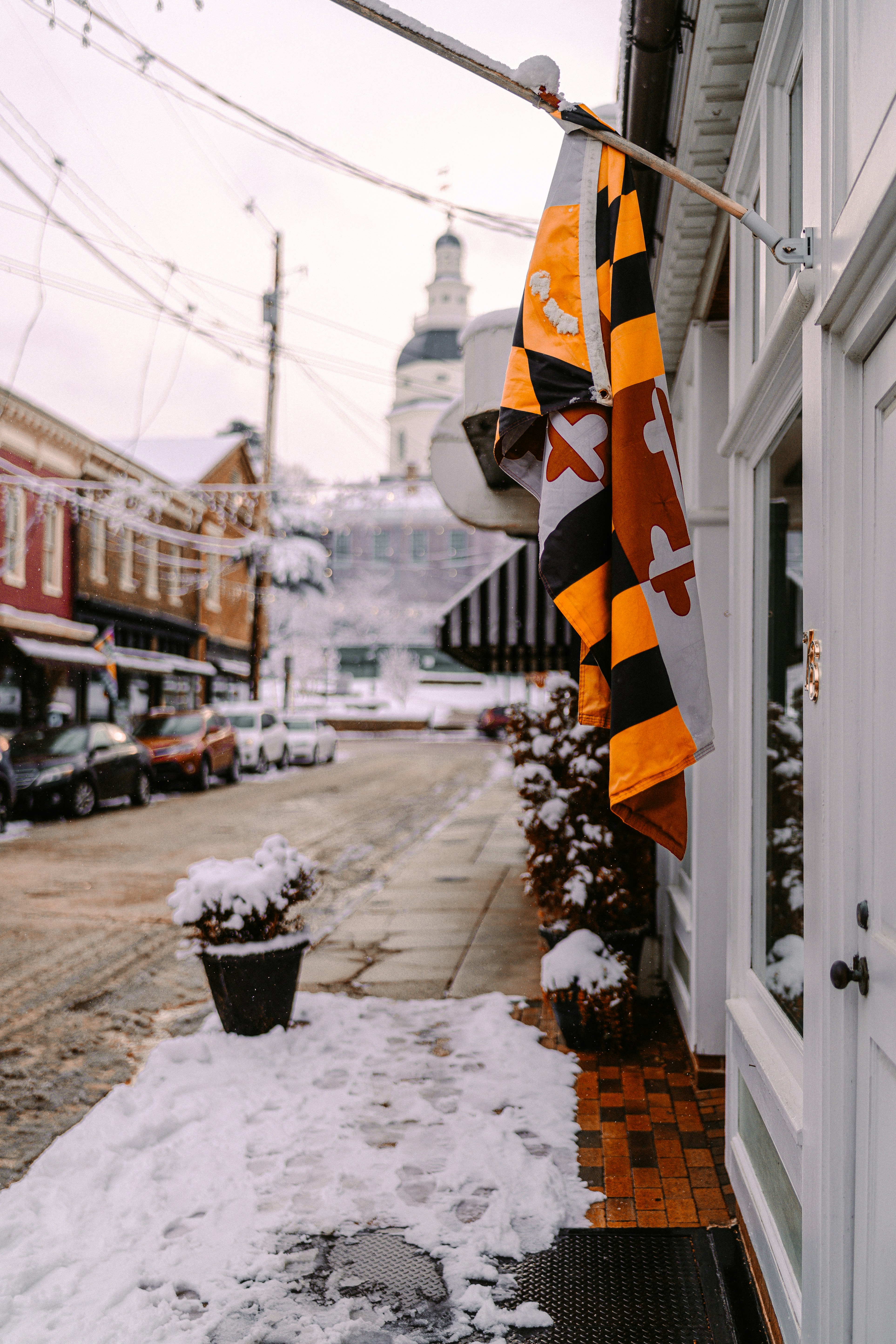 Orange-and-Black Flag Framing a Snow-Dusted Main Street